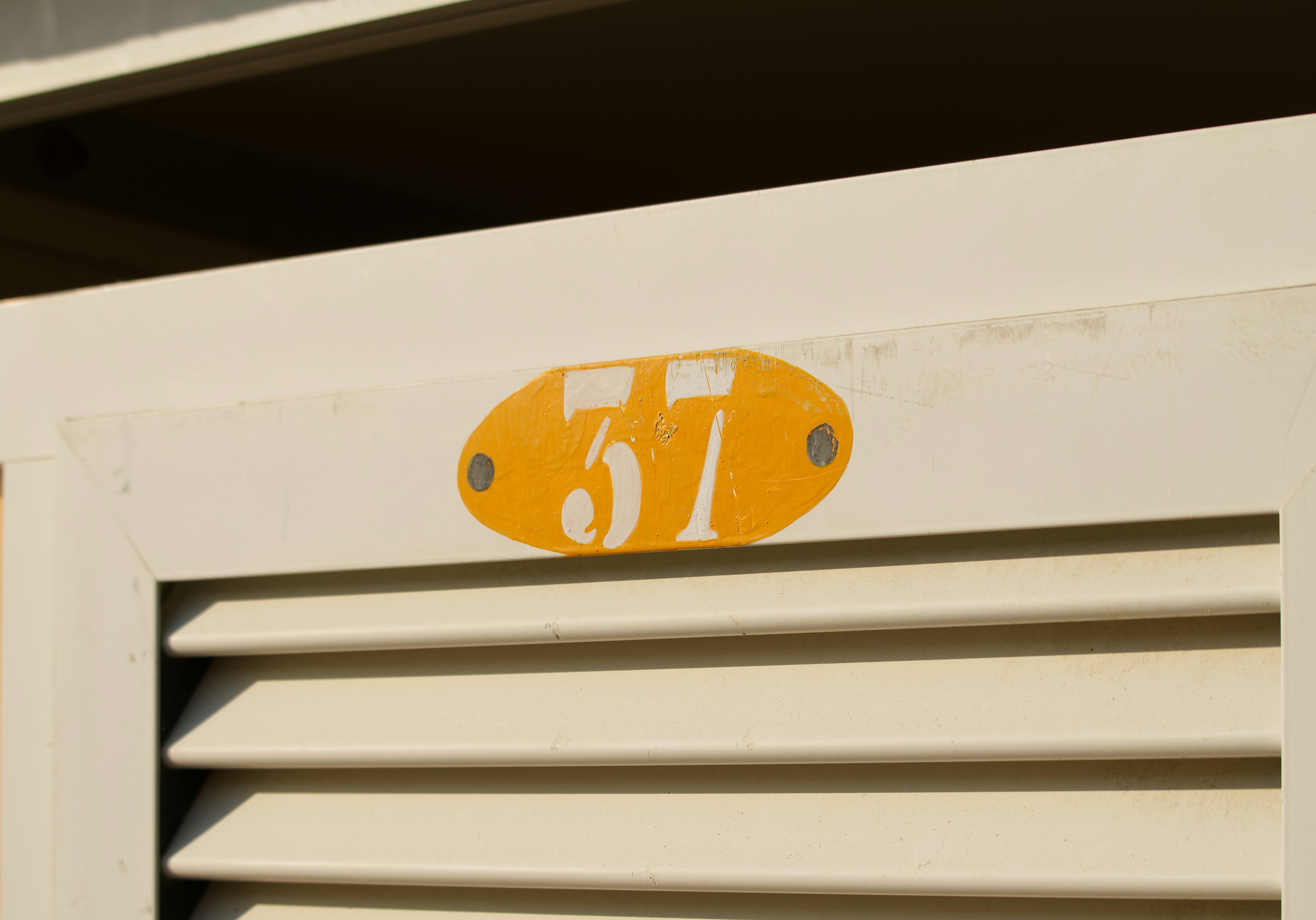 Yellow numbered plaque above a vented door