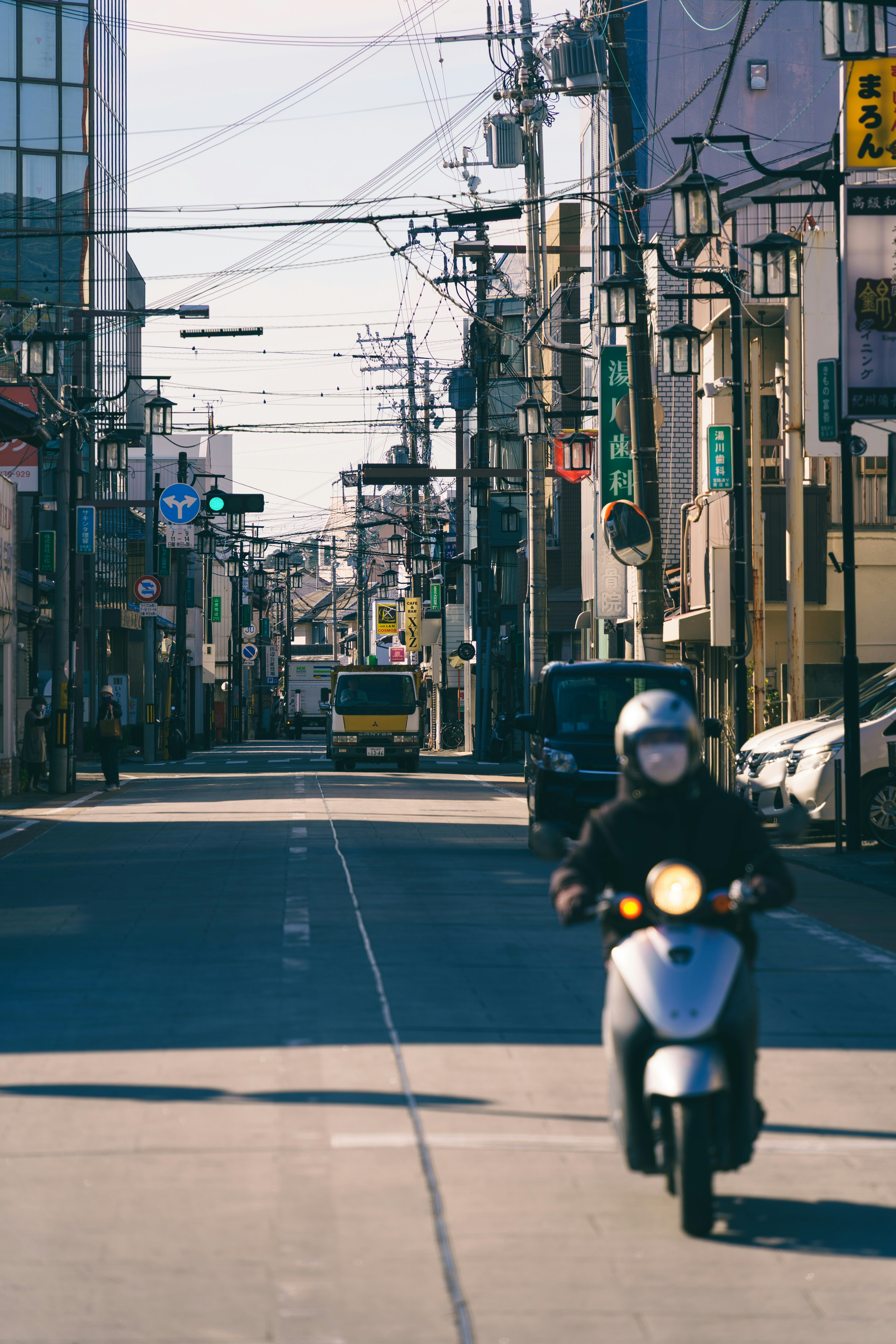 Scooter in Focus: Street Vertigo Beneath a Web of Cables