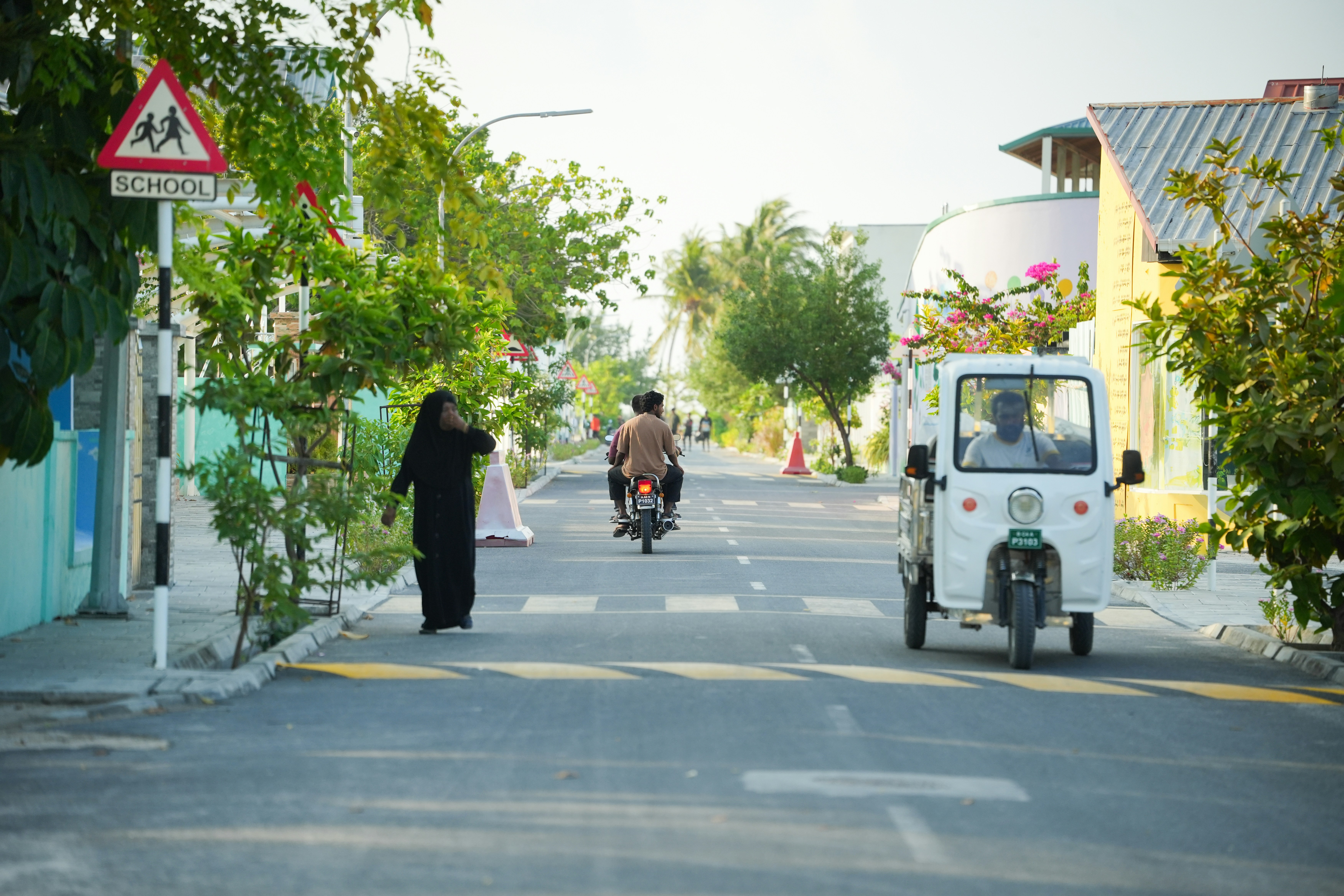 Street Scene in Quiet Town: A Motorbike, a Pedestrian, and a Tiny Delivery Vehicle