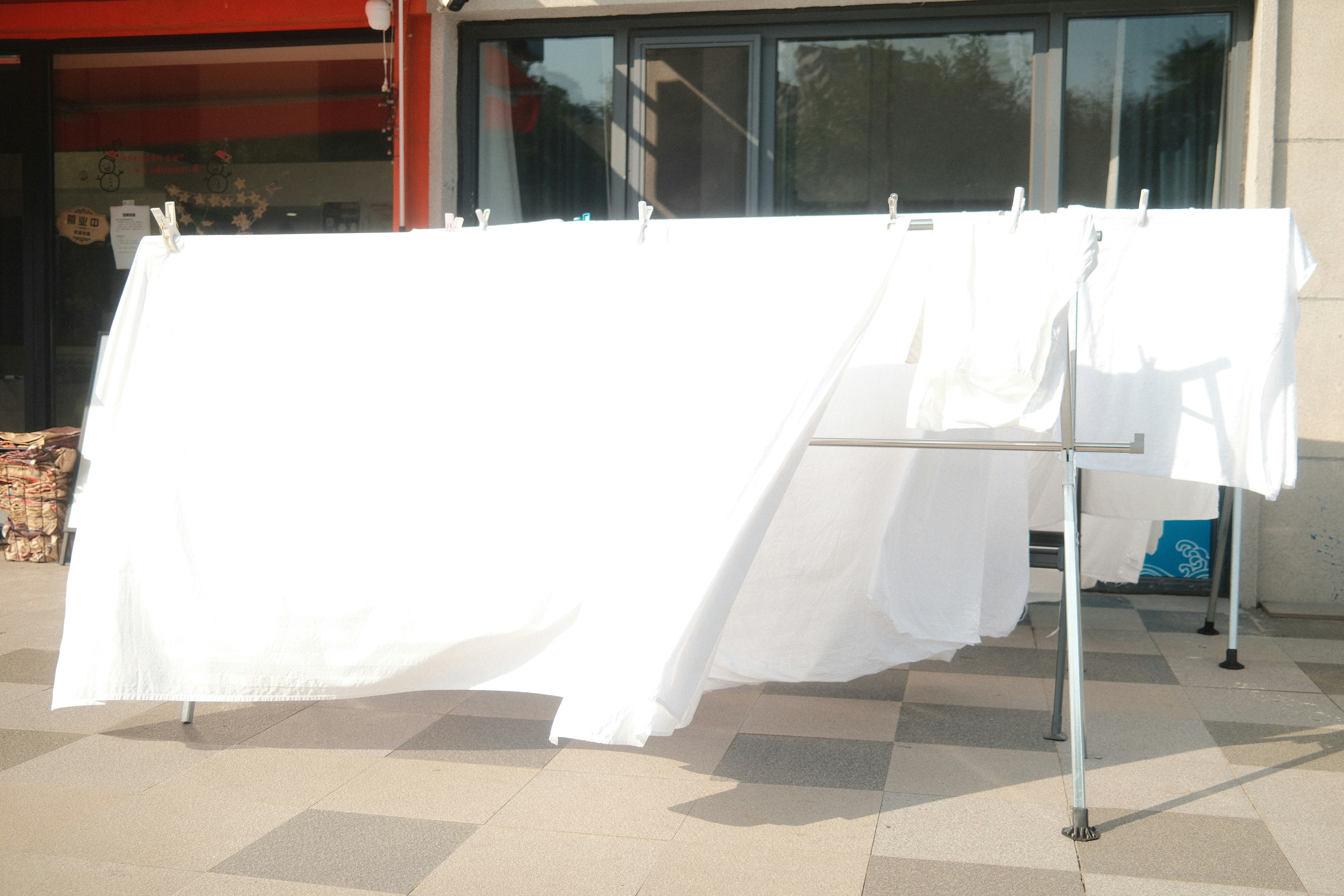 Sunlit Laundry Courtyard: White Sheets on a Rack in Quiet Morning Light
