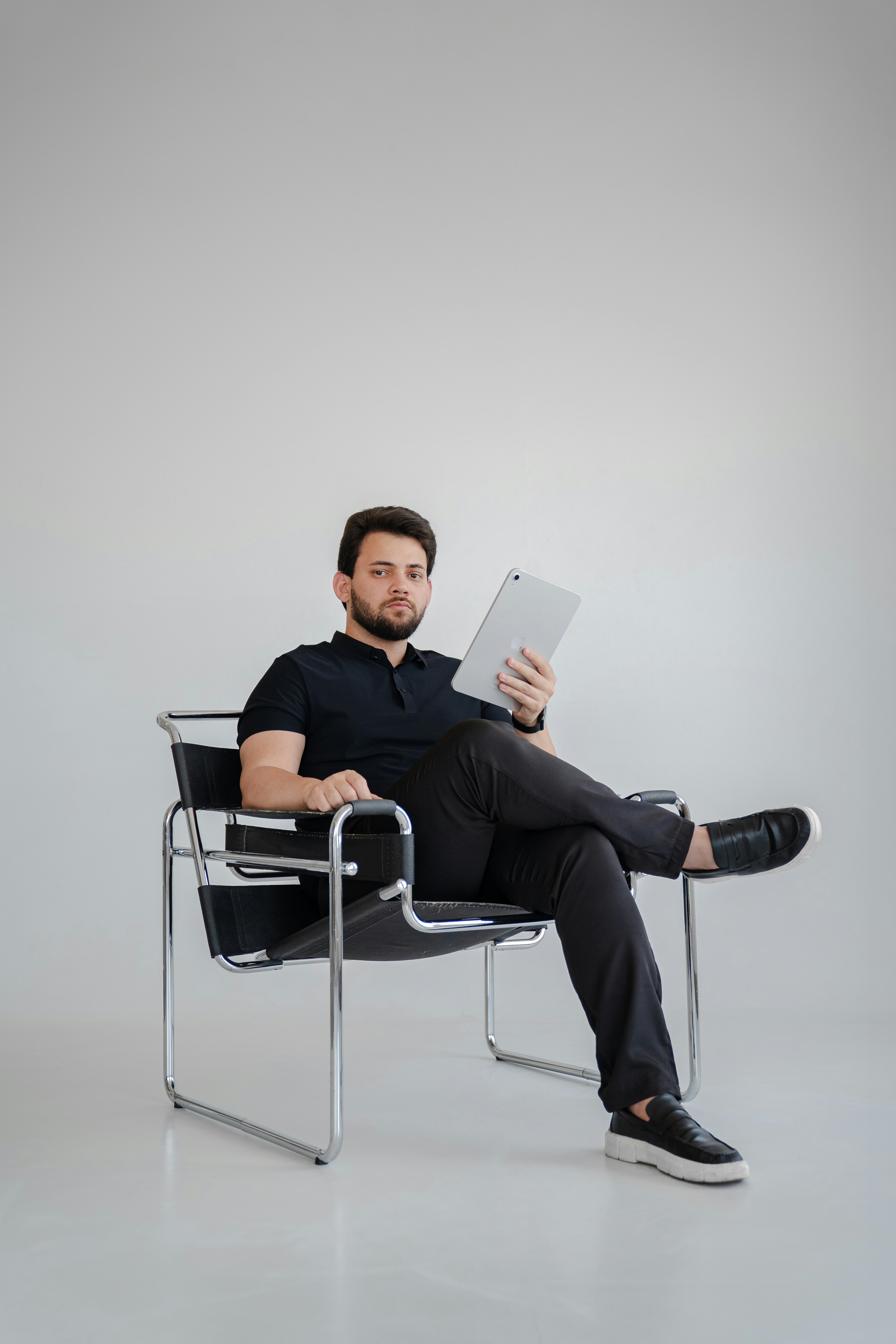Minimalist Moment: A man with tablet lounging in a stark studio