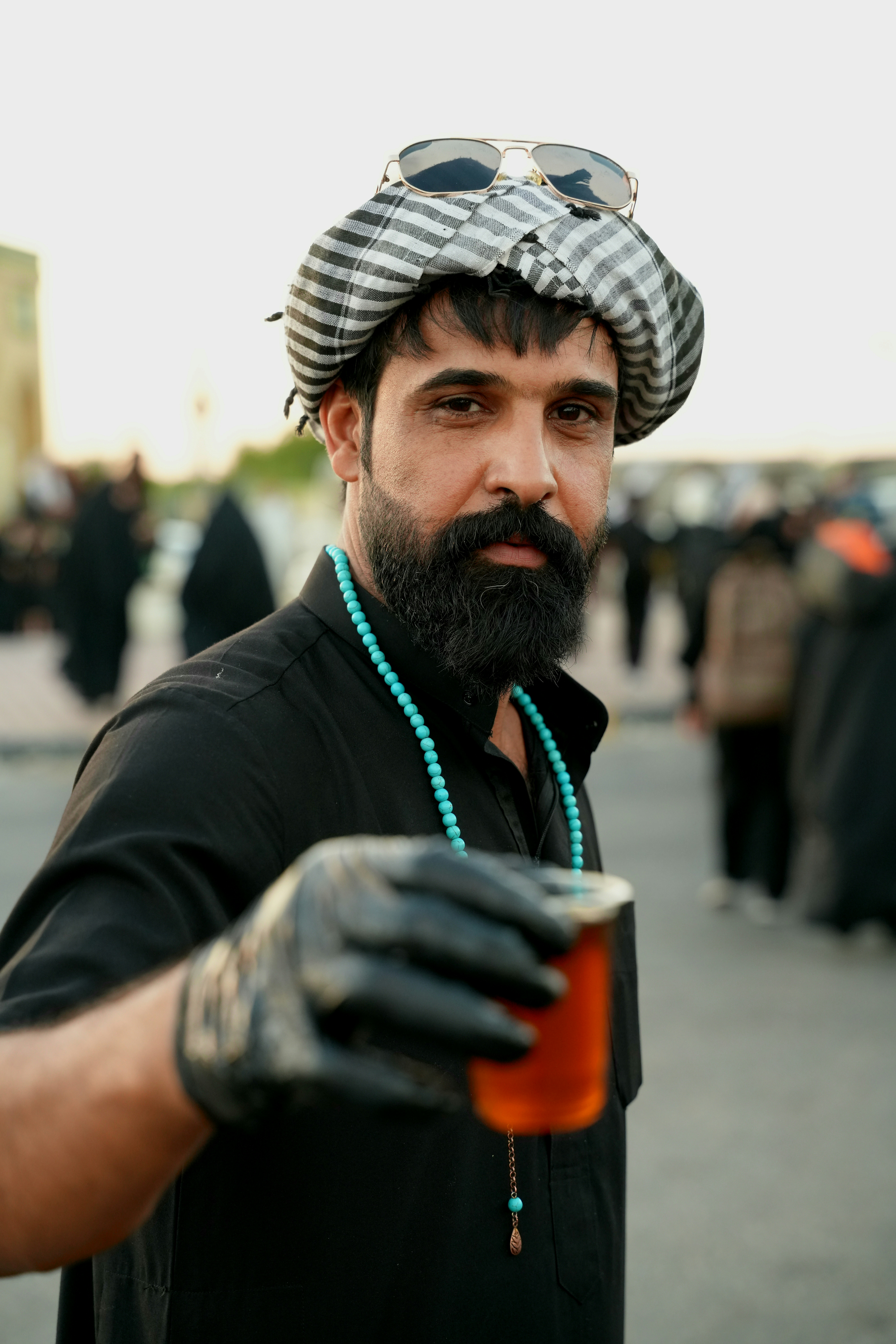 Bearded Host with Turquoise Bead Necklace at a Warm Outdoor Gathering