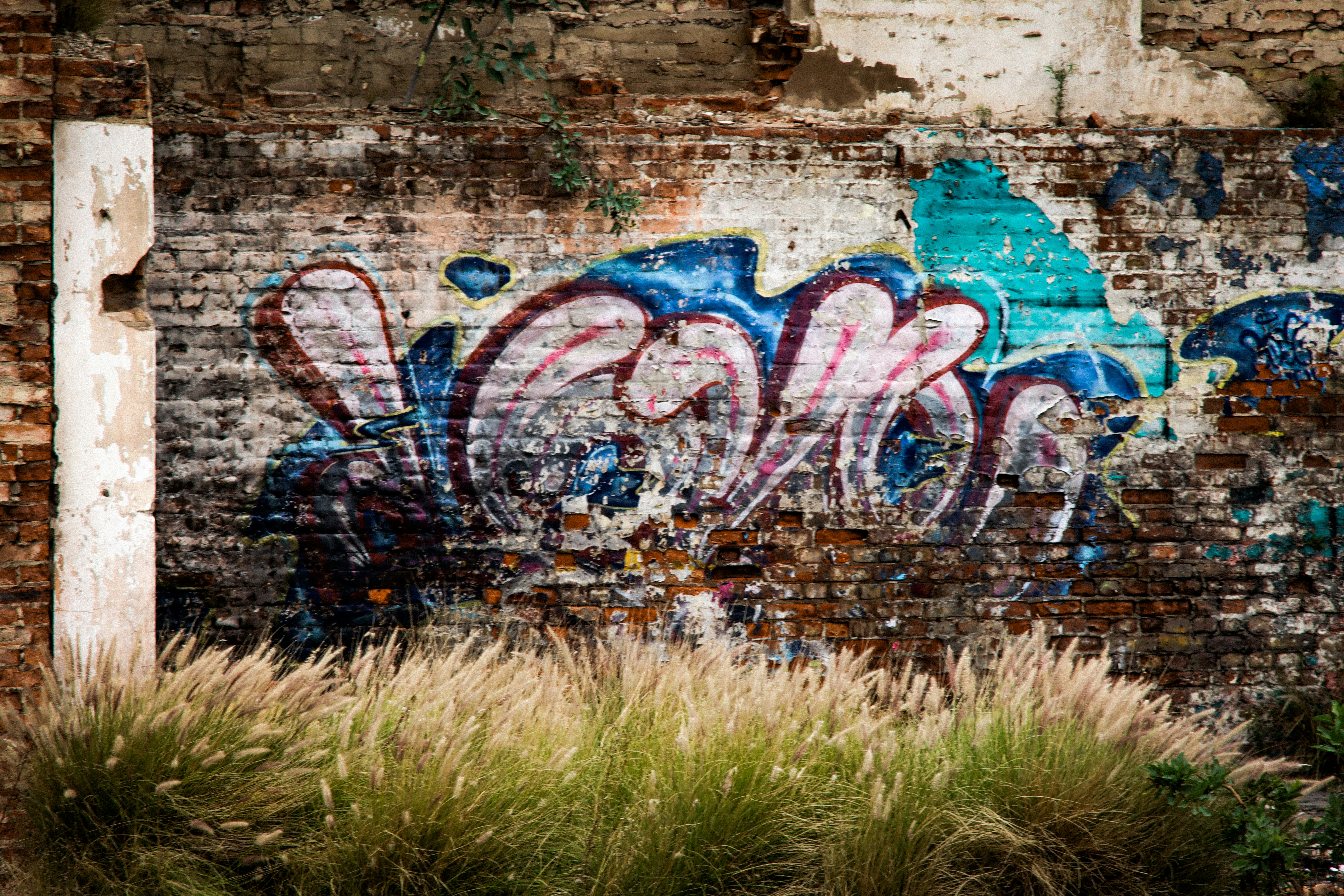 Graffiti chronology on weathered brick: color pops over old mortar