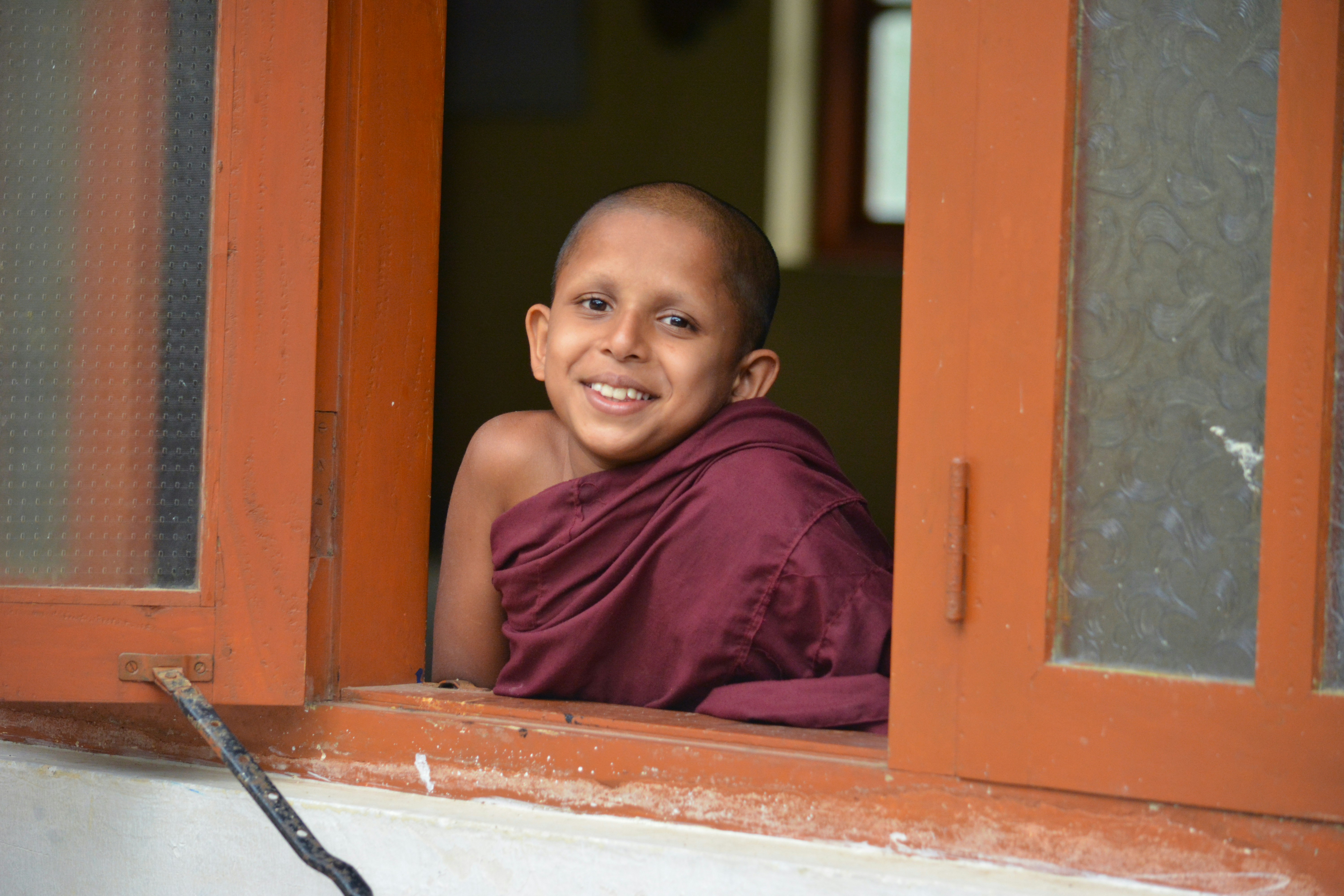 Smiling monk at the doorway: warm light framing a humble portrait
