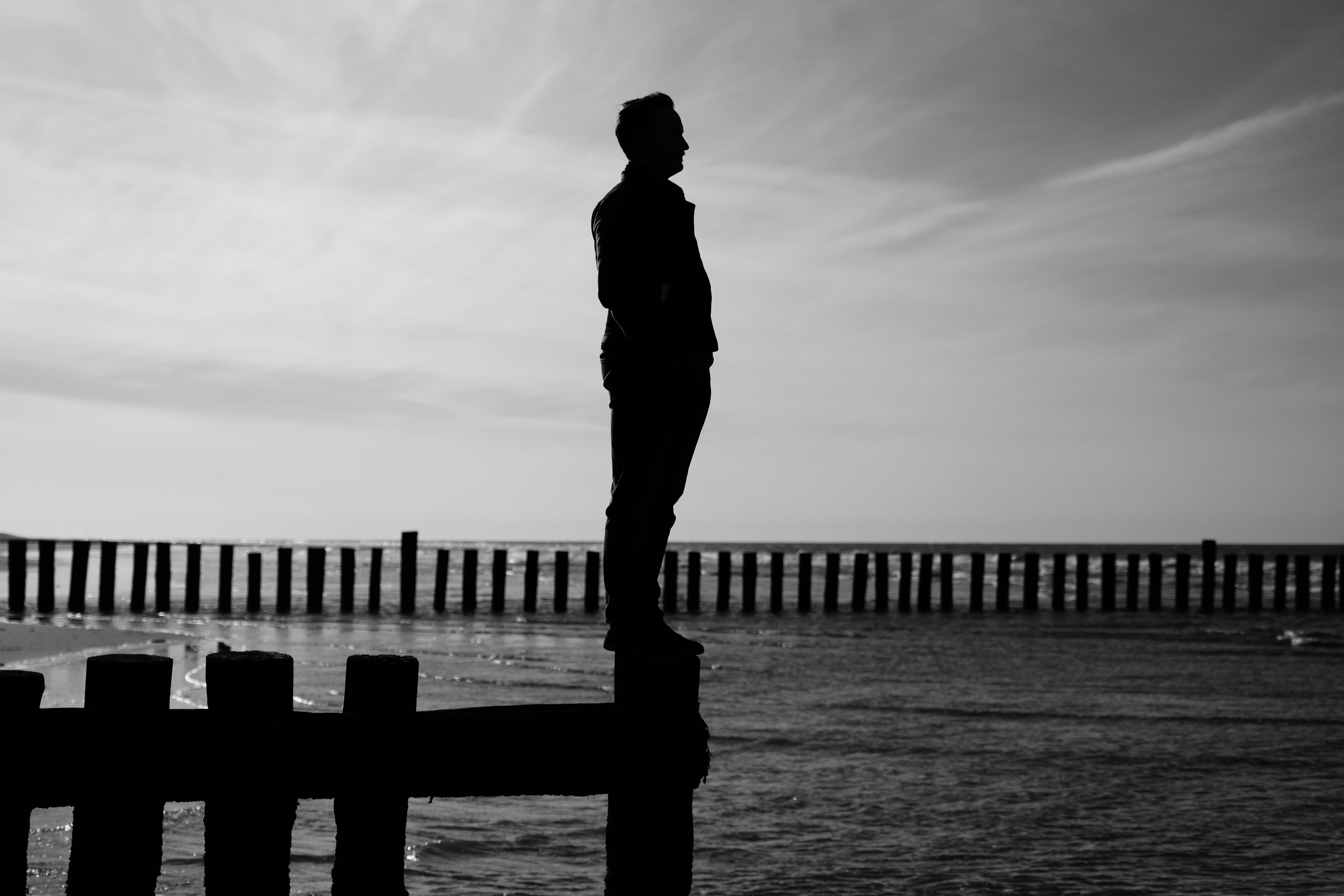 Silhouette at Distant Pier: a solitary figure against the sea
