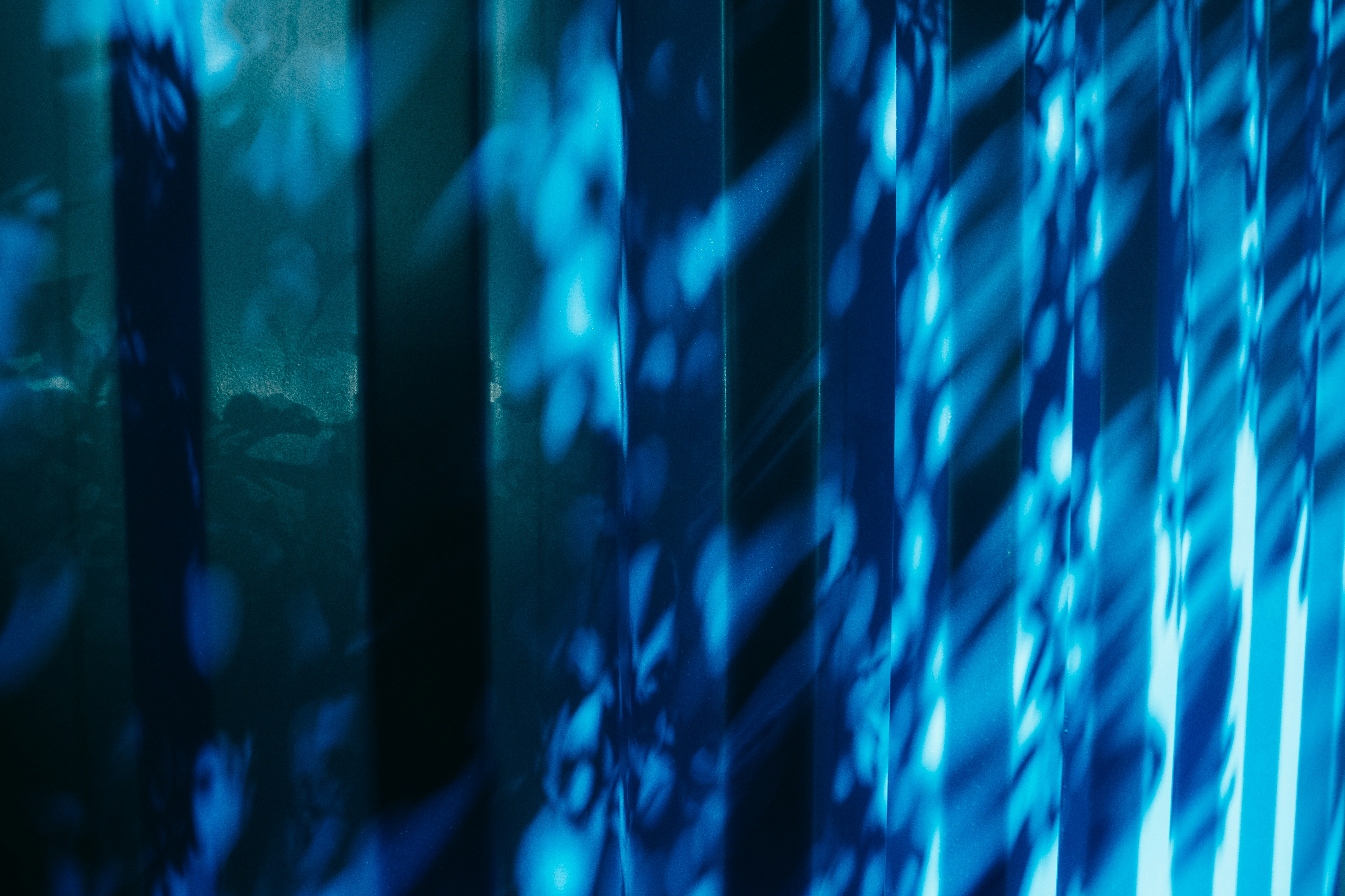 Prismatic Blue Reflections: Vertical Light Trails Across a Glass Facade