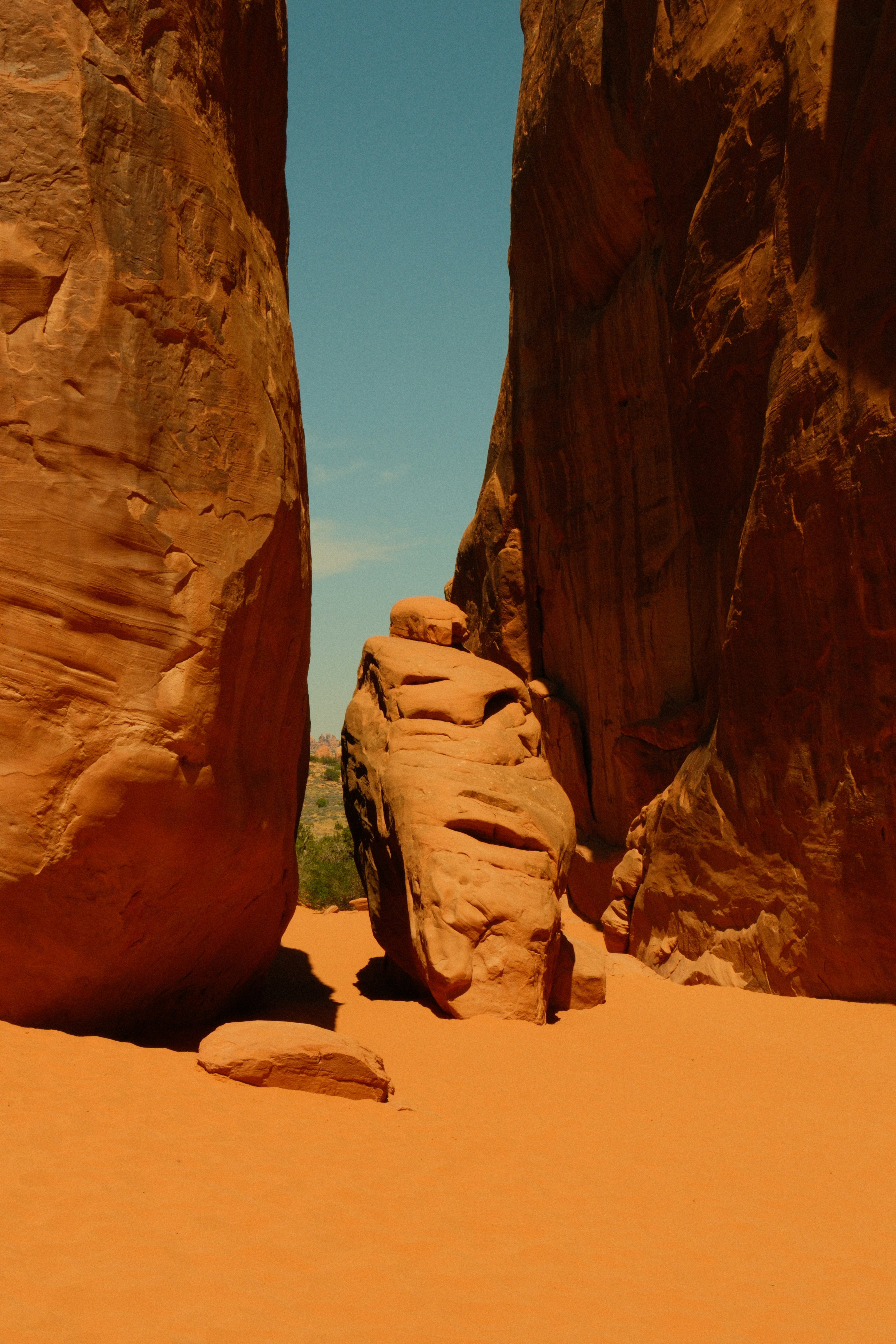 Narrow sandstone passage framed by towering orange cliffs