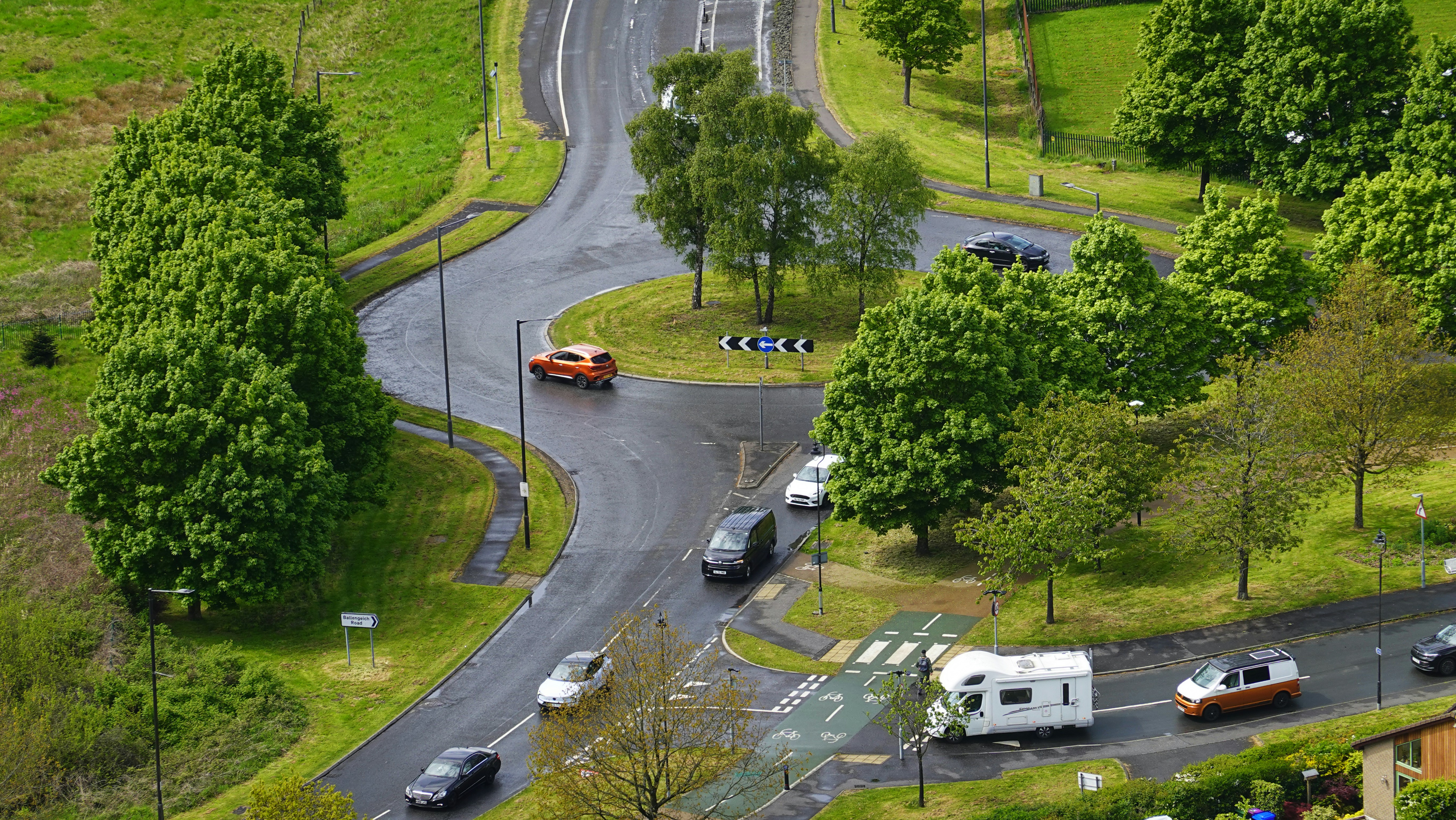 Roundabout Rhythm: Aerial Drive Through Lush Green Curves