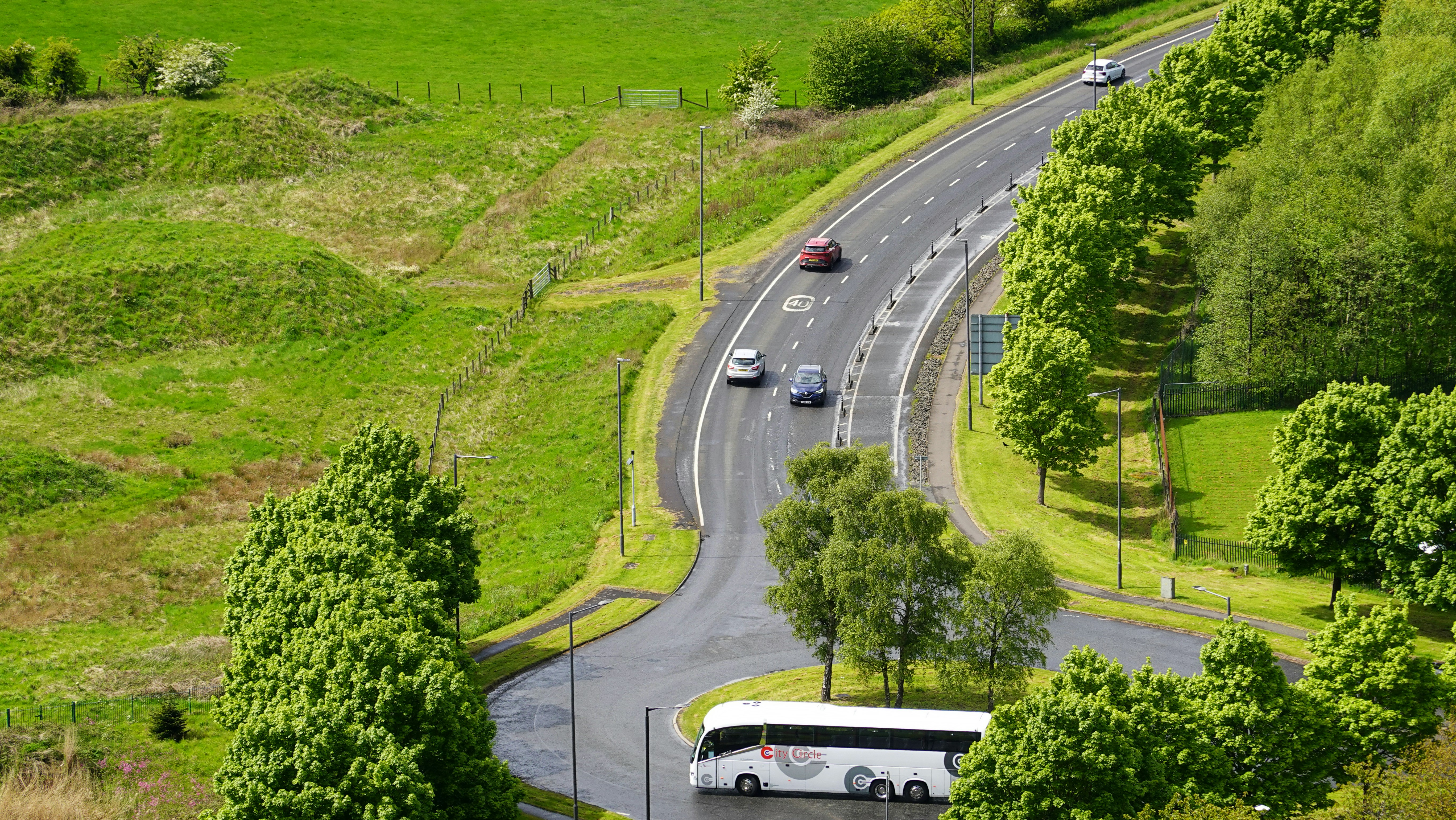 Curved Highway Ballet: A White Bus Leads the Green Corridor