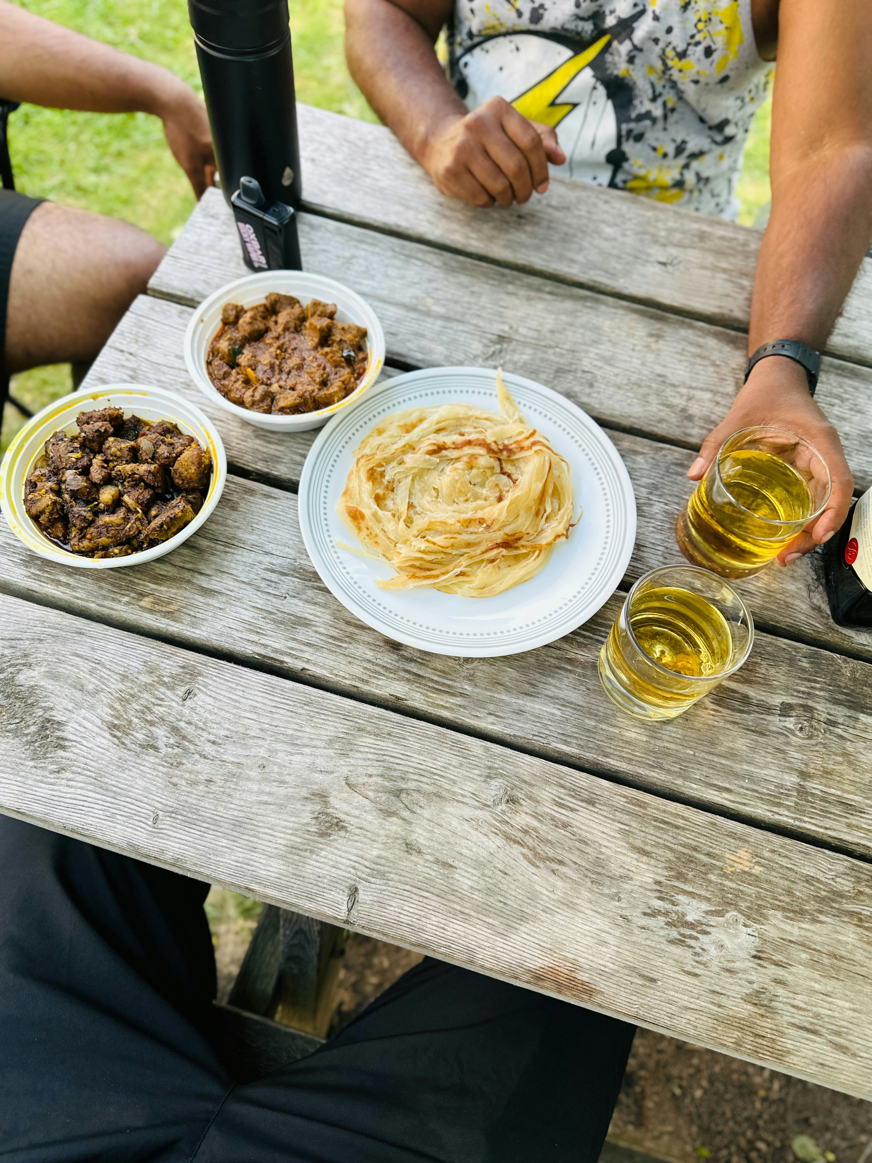 Outdoor feast at the communal table: pastries, bowls, and frosty mugs