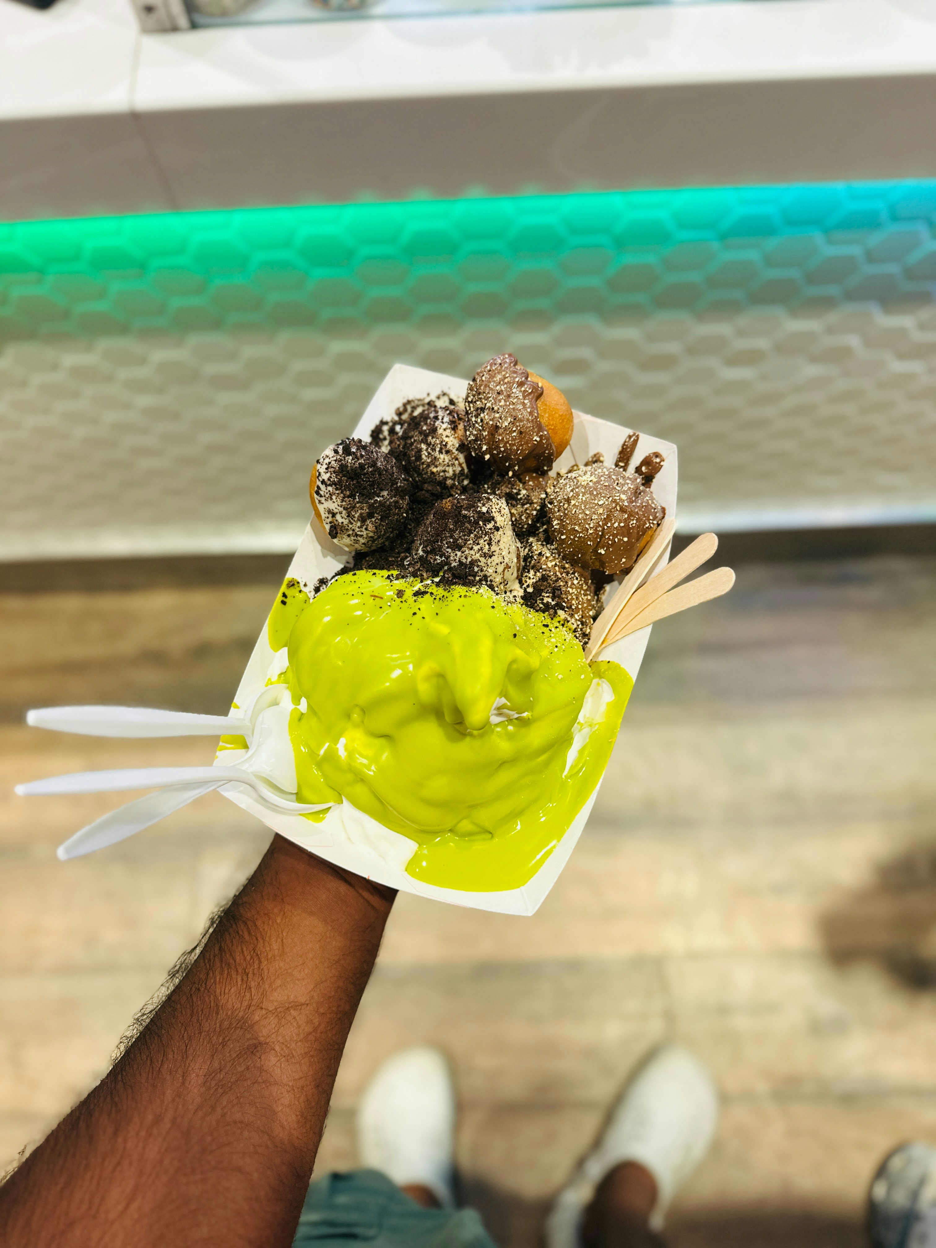 Lime-green dessert cup in hand against a tiled neon backdrop