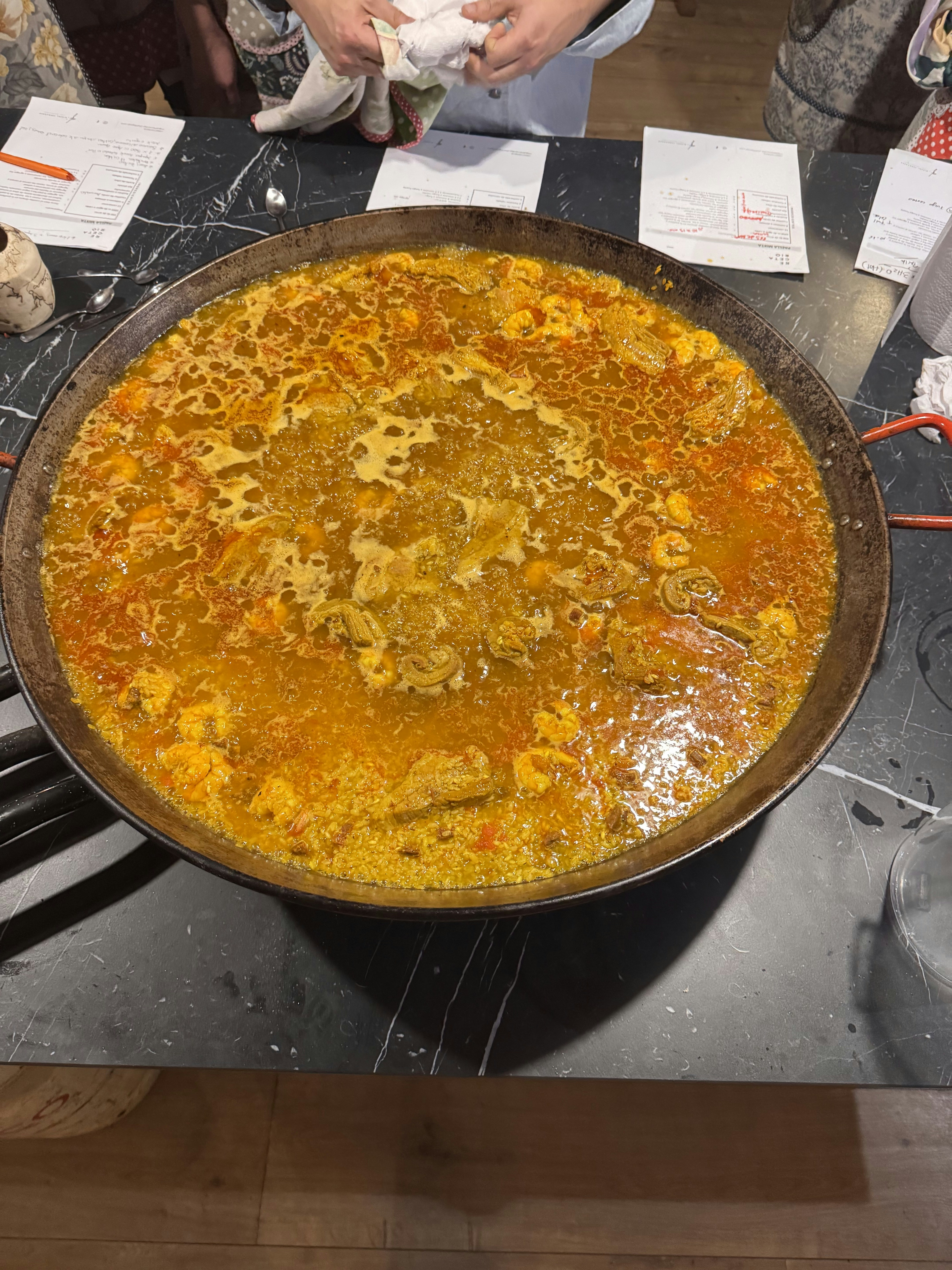 Family-style paella in a wide skillet at a communal table