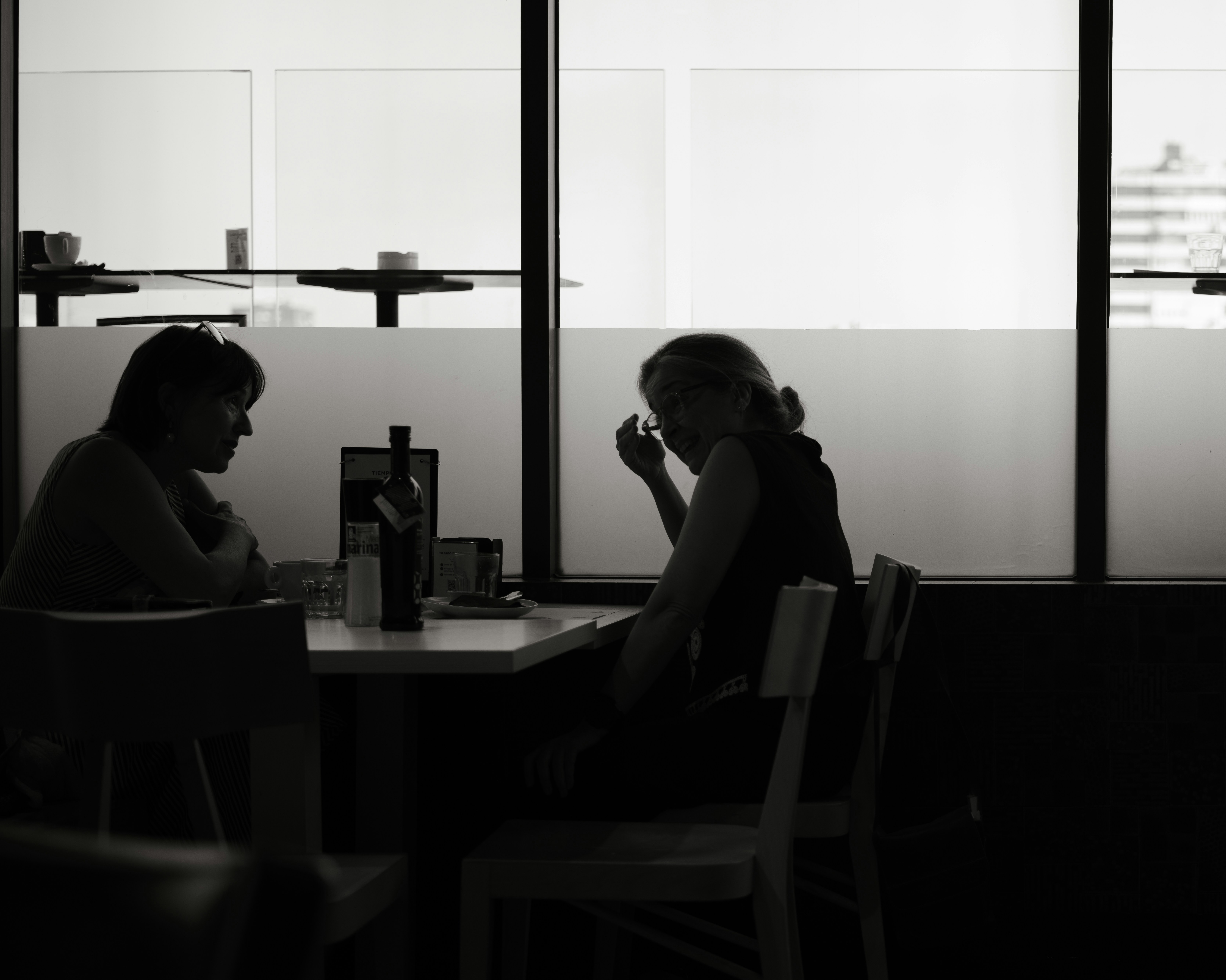 Silhouettes at Dusk: A Quiet Table with Two Figures in Shadow