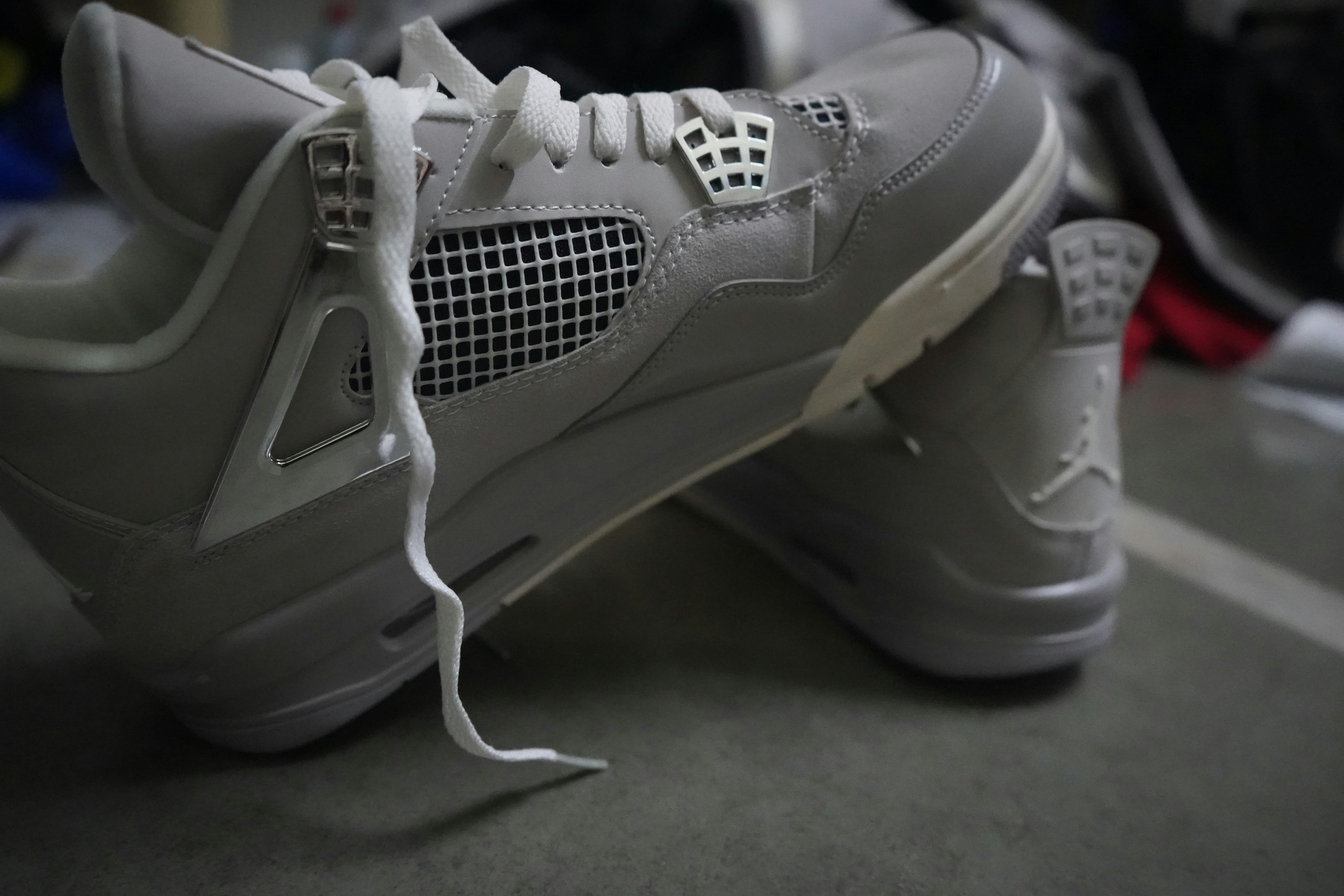 Quiet Confidence: A Pair of Light Gray Sneakers Rest on a Concrete Floor