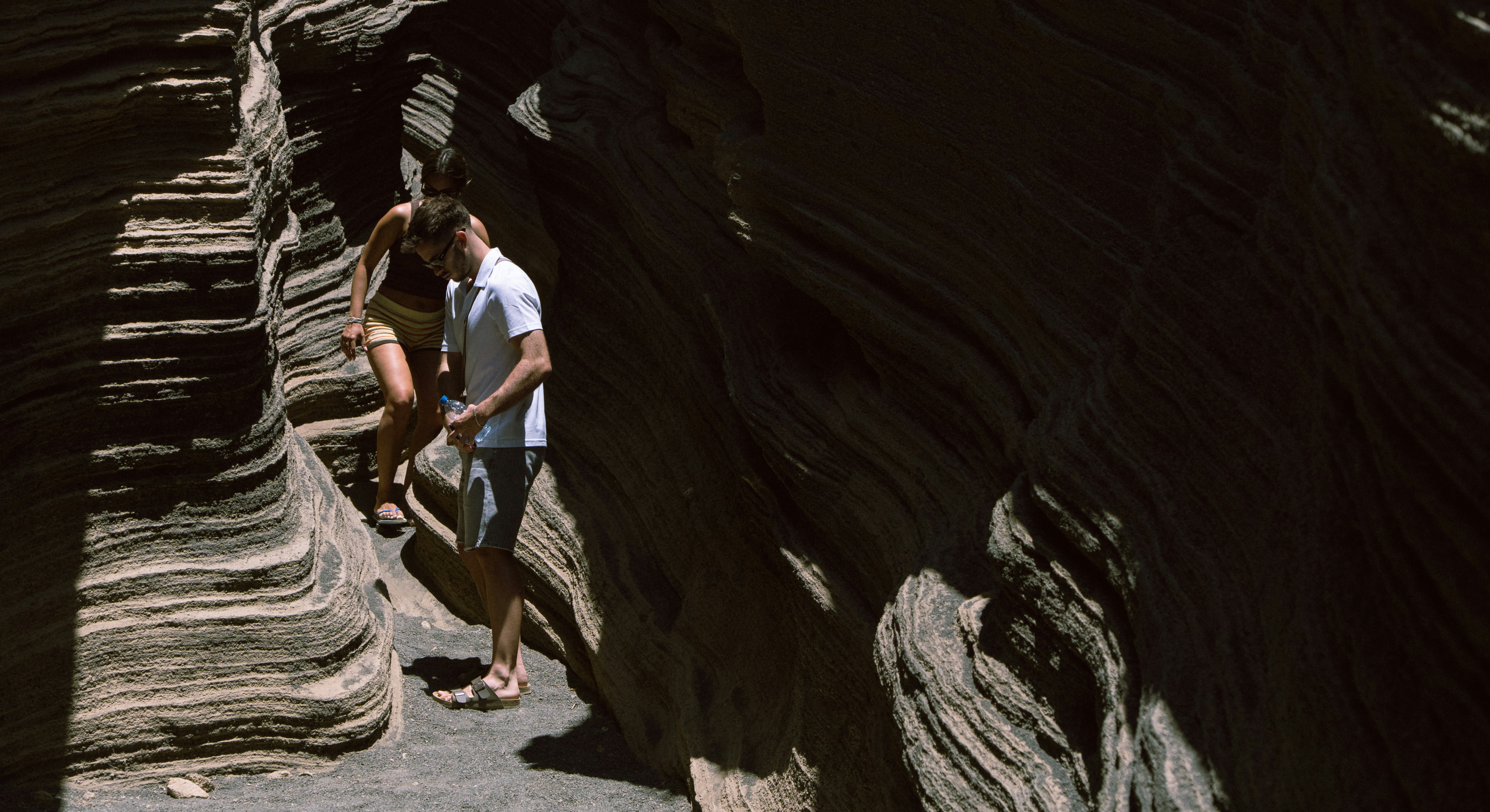 Narrow Canyon Steps: Two Figures Navigate a Sunlit Pass