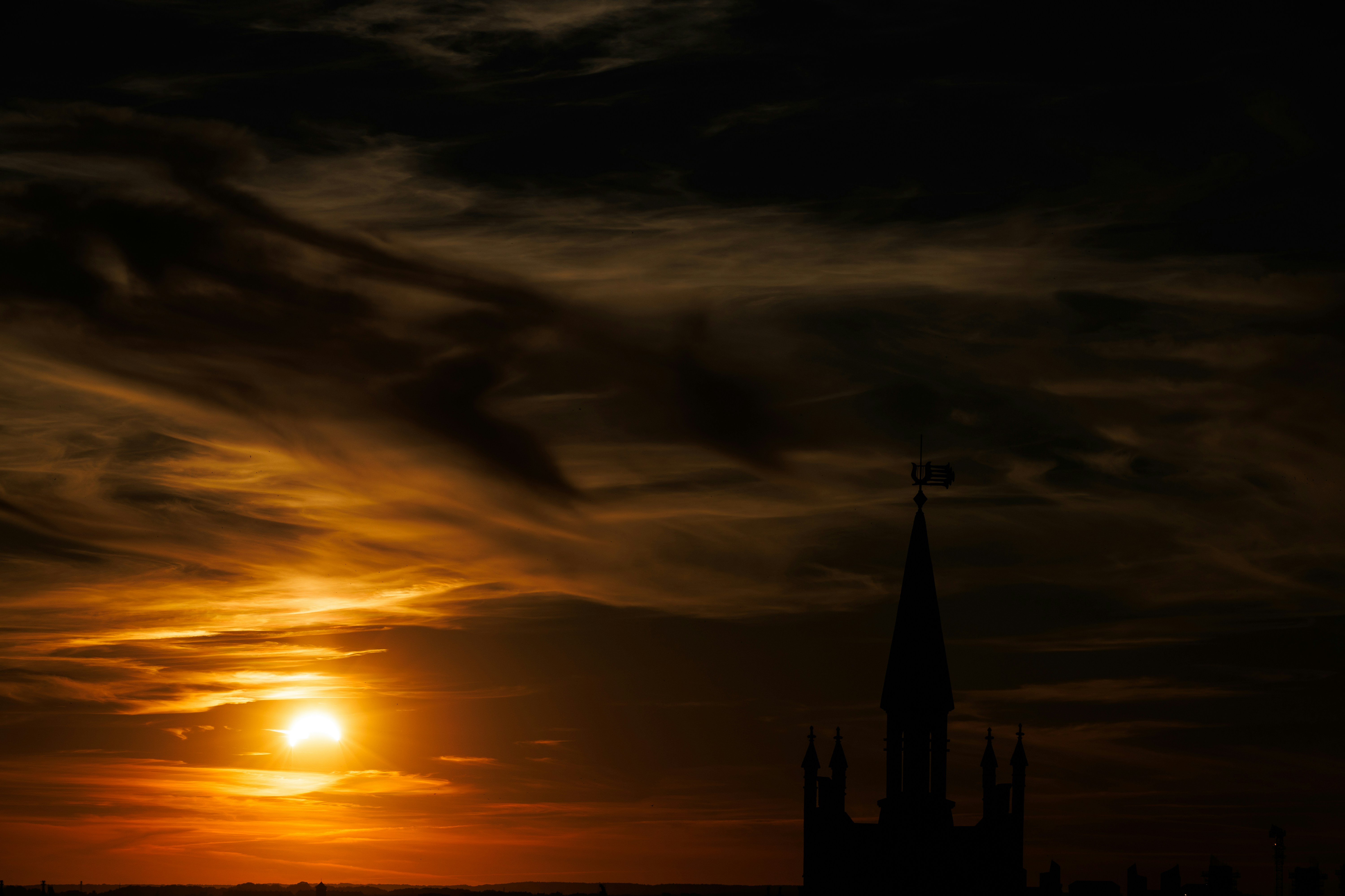 Silhouette at Dusk: A City Spire Beneath a Fiery Sky