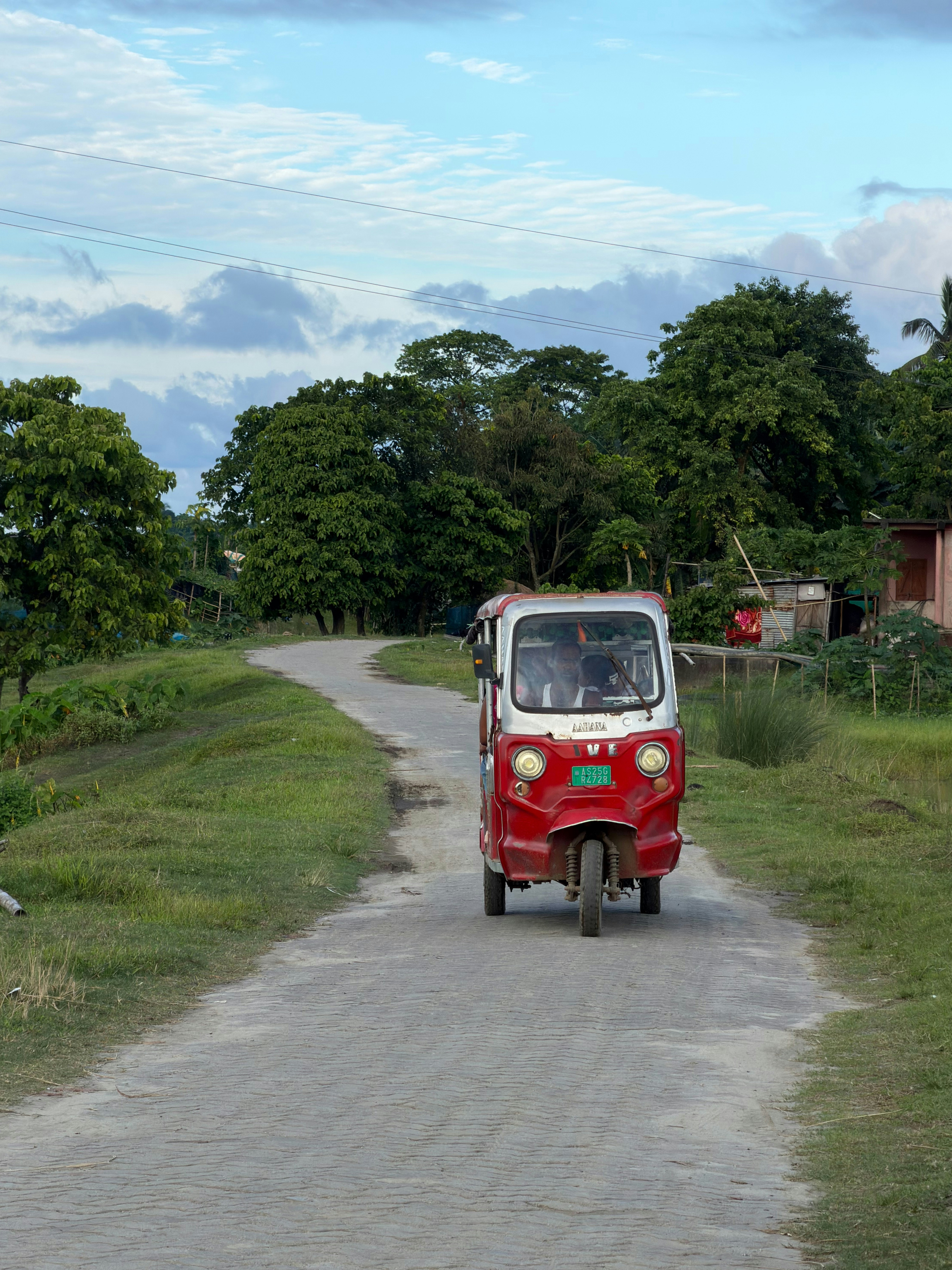 Red Trag as the Road Narrows: A Tiny Auto Rides Through Rustic Green