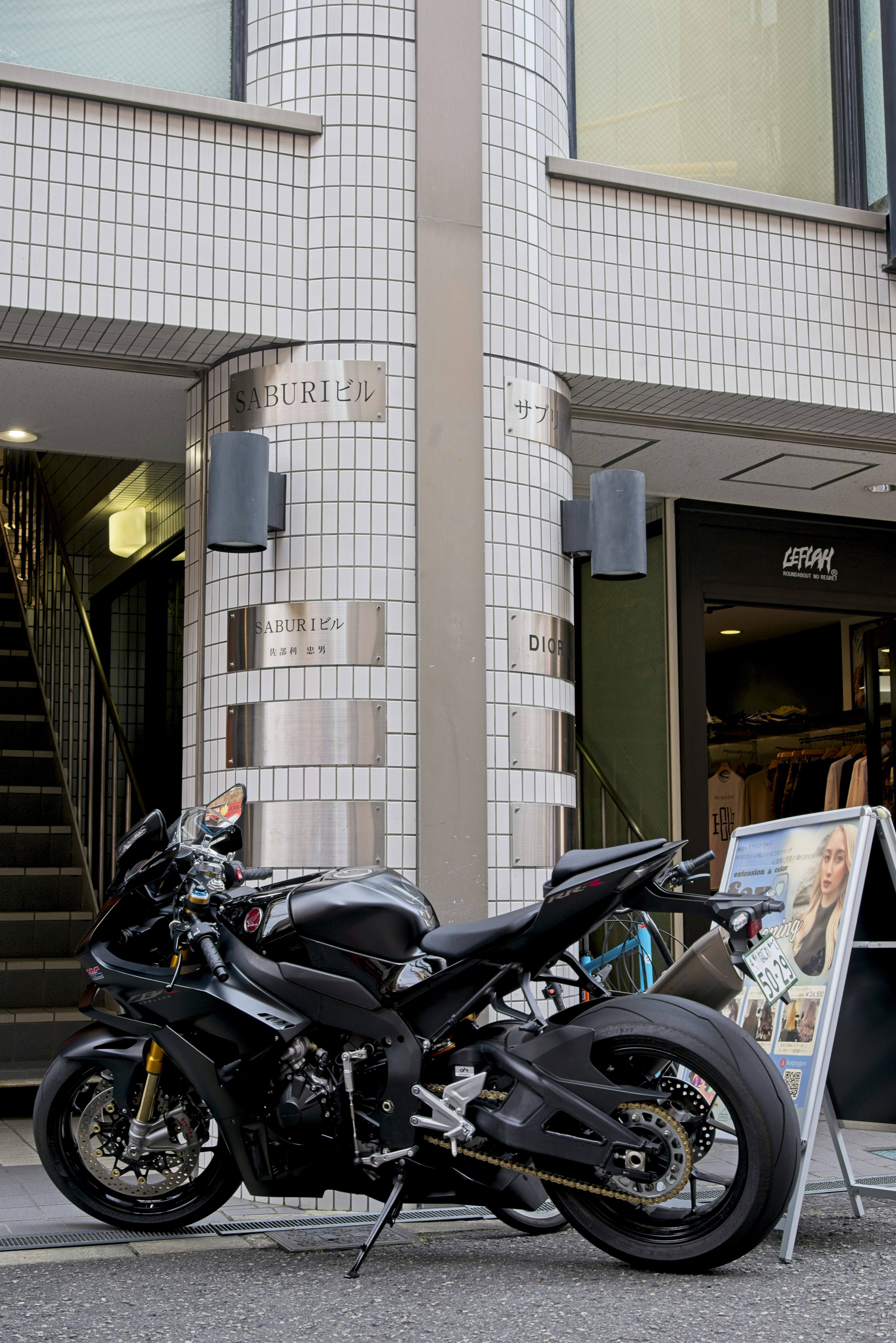 Street Corner Power: A Black Motorcycle Pauses Before a Modern Facade