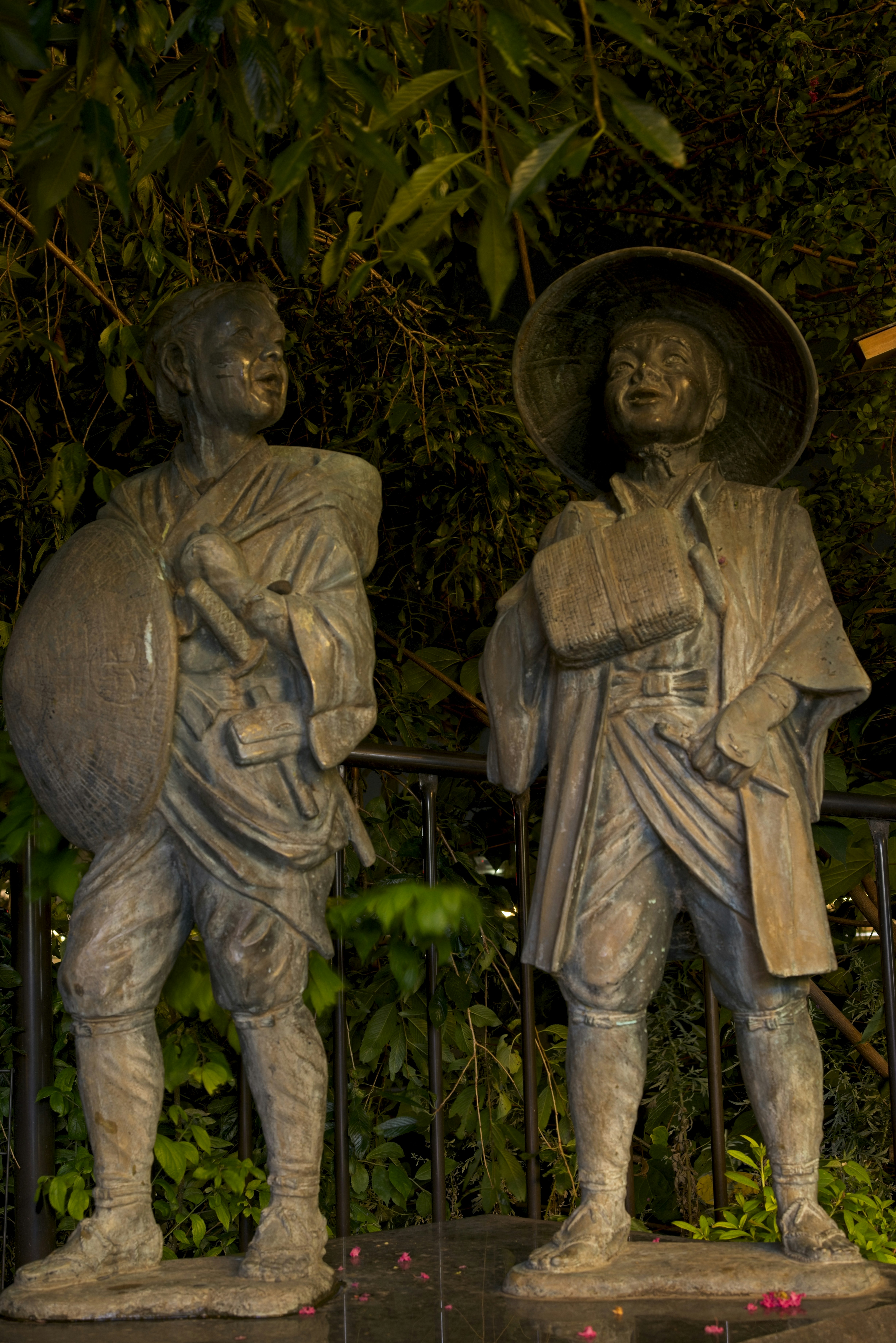 Guardians in Quiet Light: Stone Figures Beneath Foliage