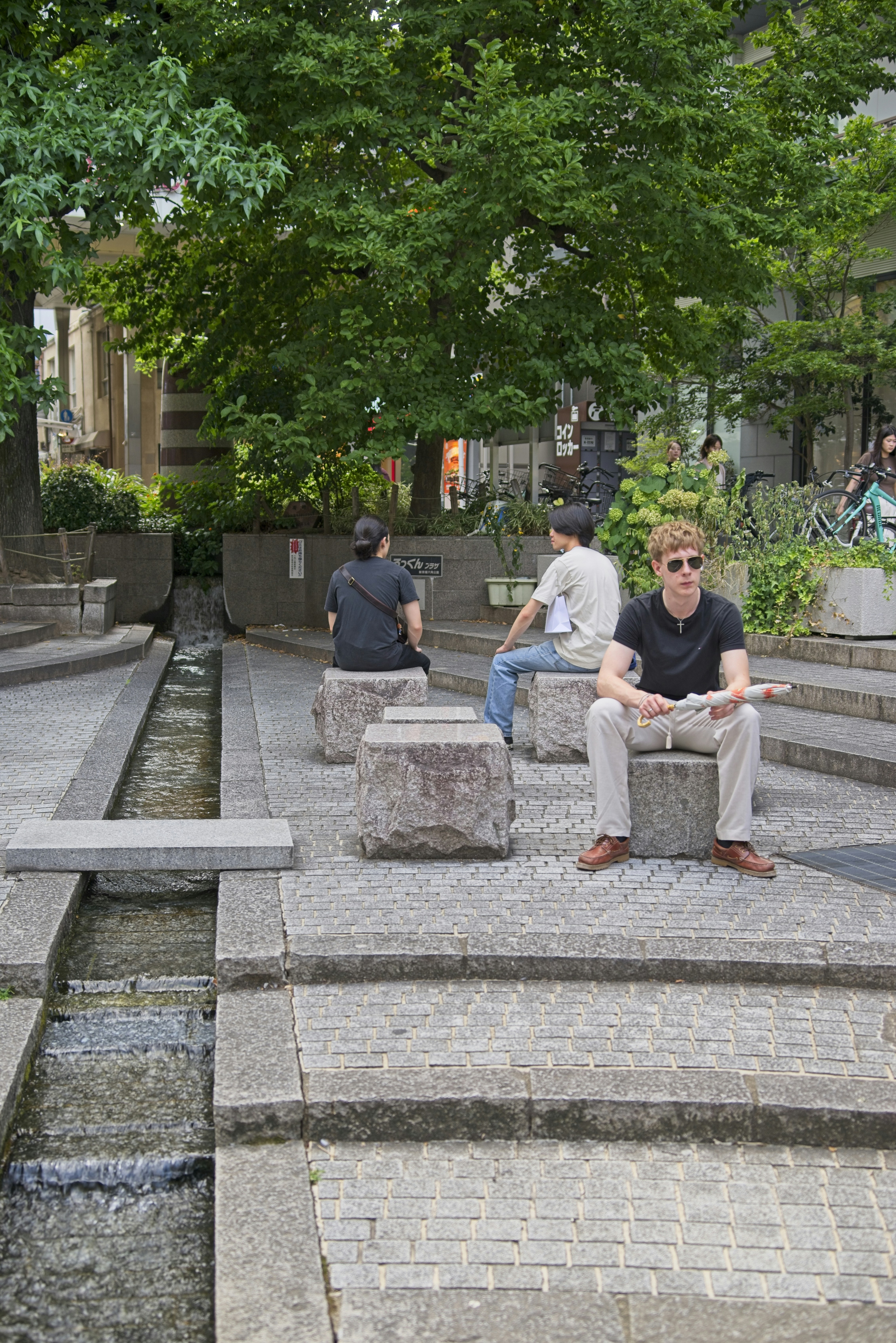 City Courtyard Moment: Three Friends Rest by a Sunlit Fountain