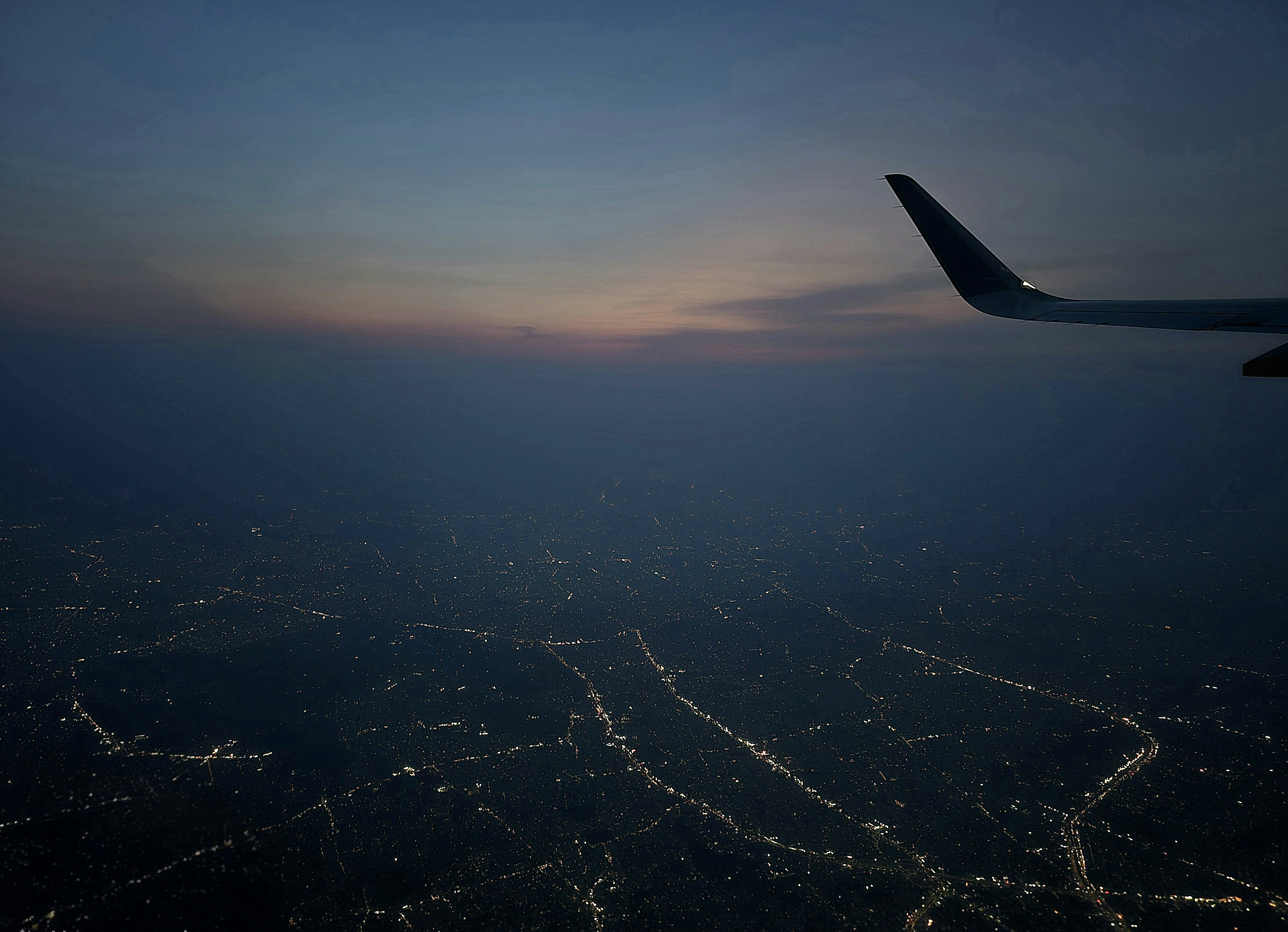 Wings Over Lights: Dusk Flight Above a City Grid