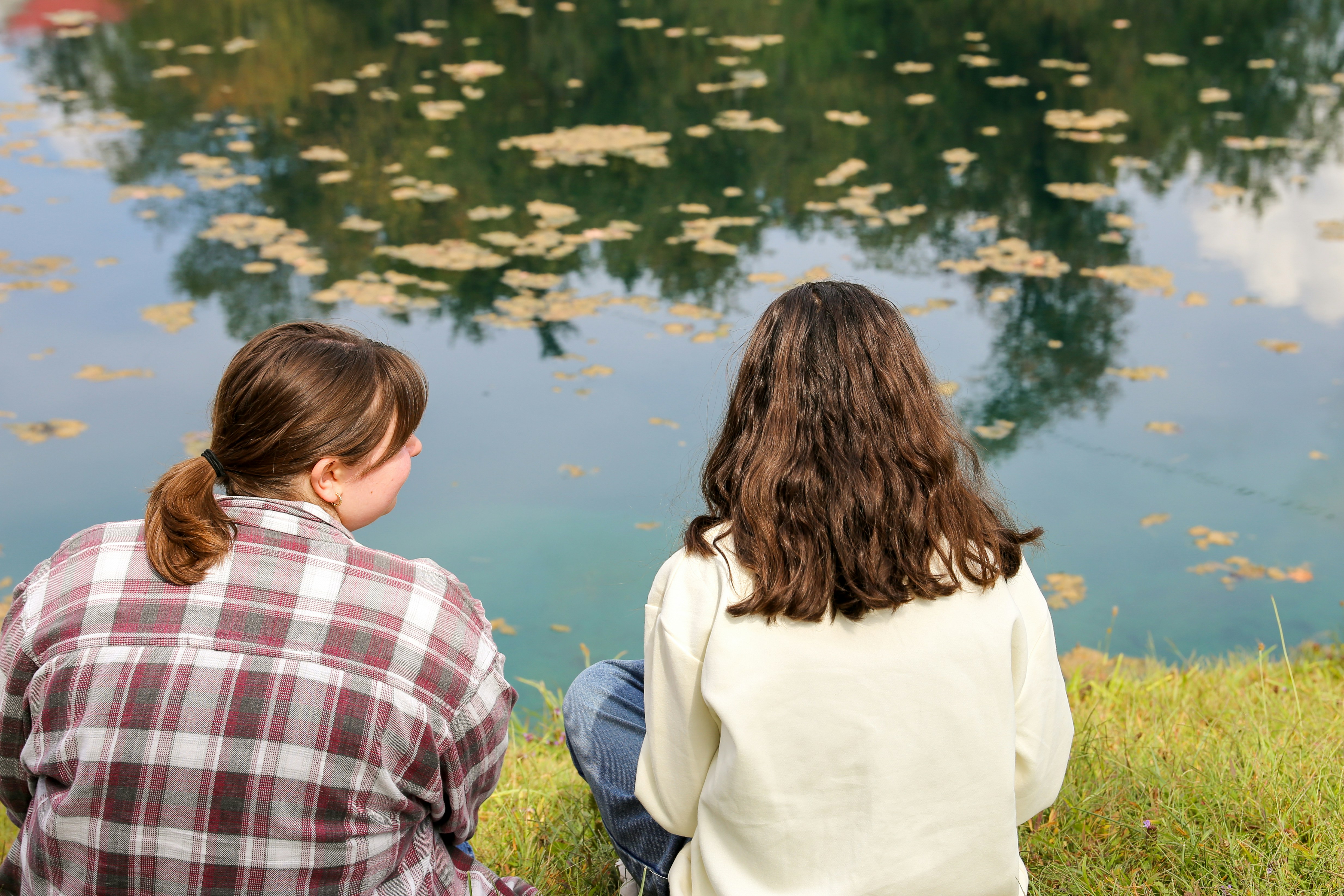 Quiet Presence by the Pond: Two Friends in Sunset-Tinted Conversation
