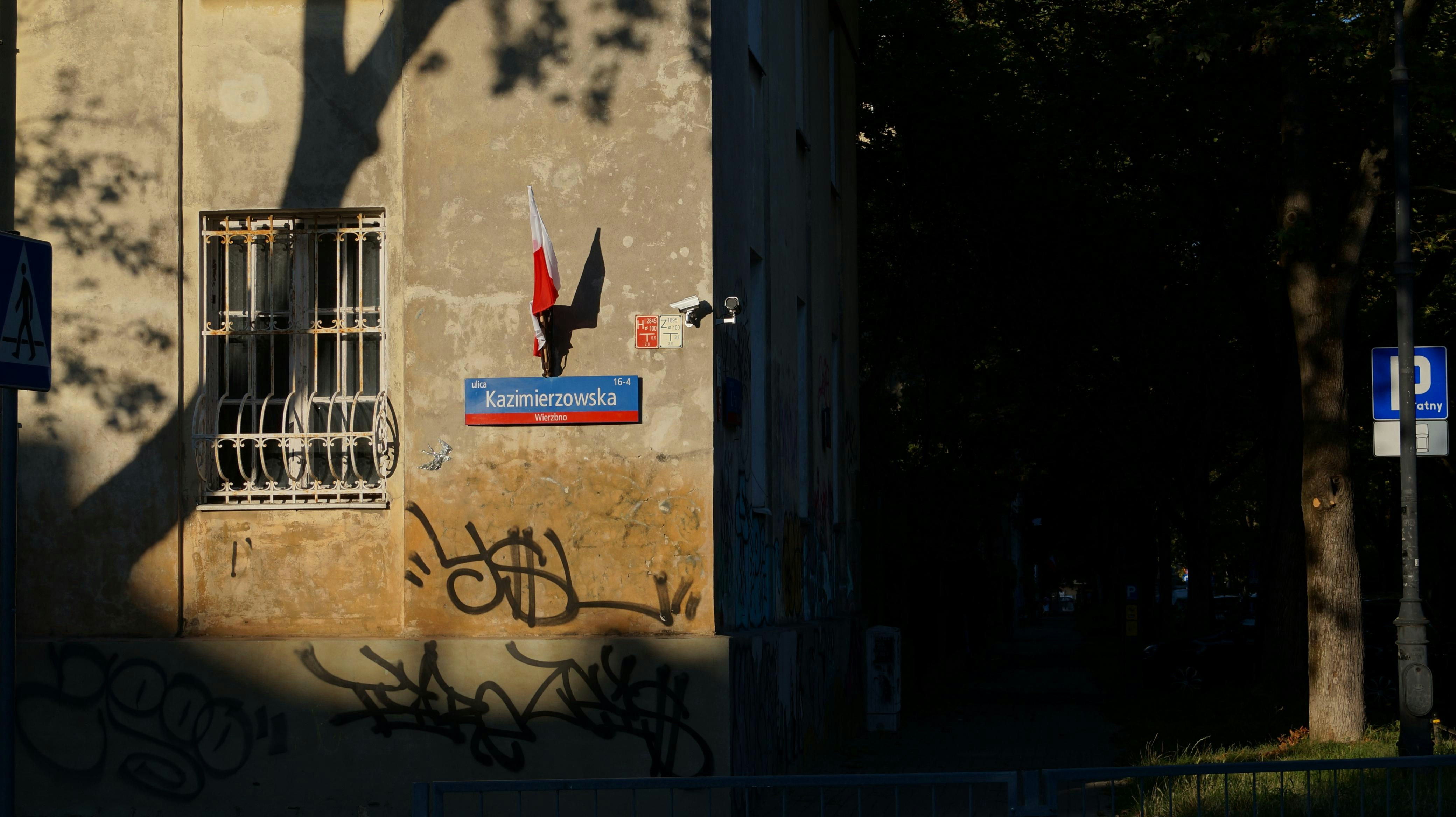 A street sign reading Kazimierzowska on a weathered building corner in Warsaw