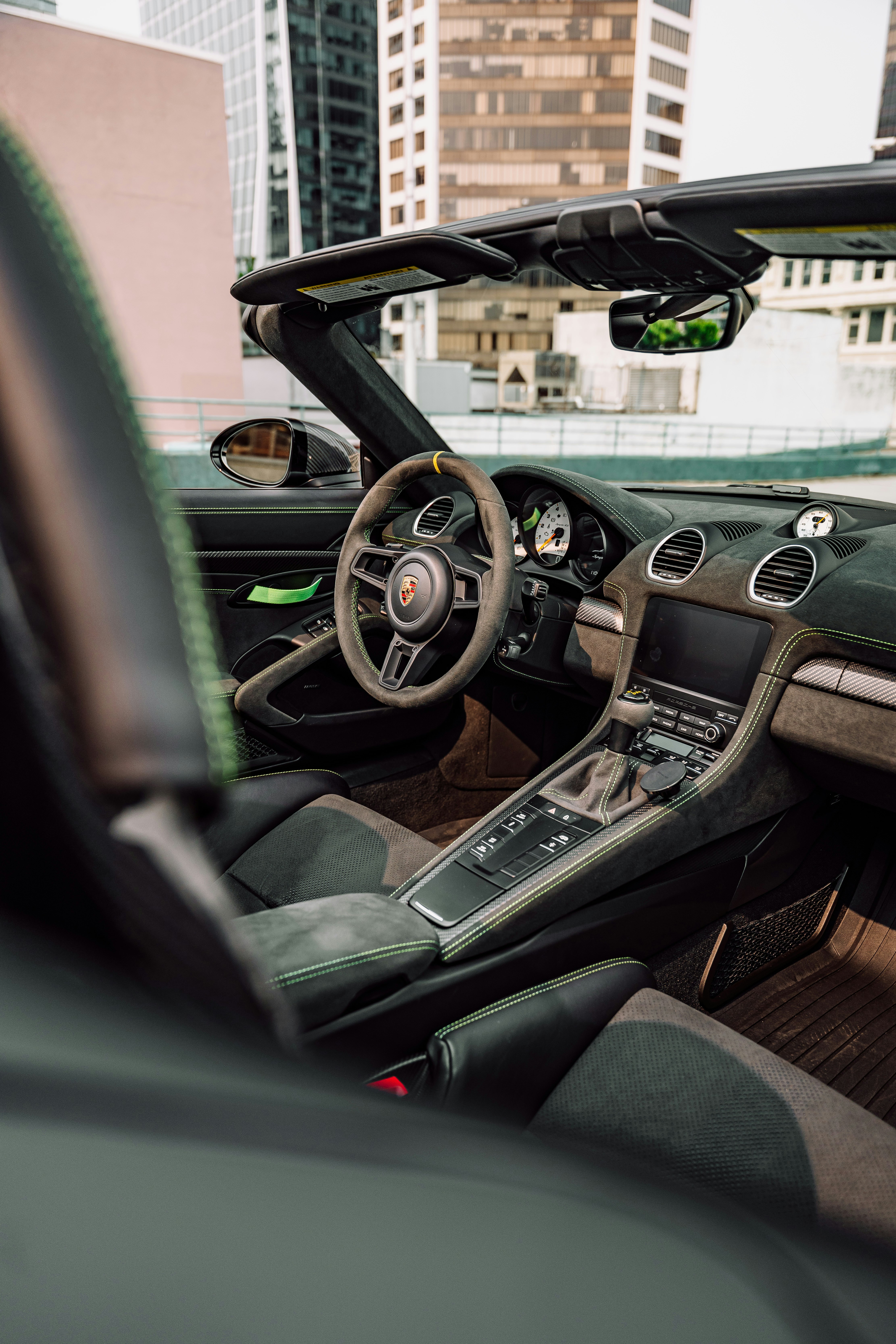 Porsche cockpit in motion: leather, gauges, and steering in a sunlit city drive