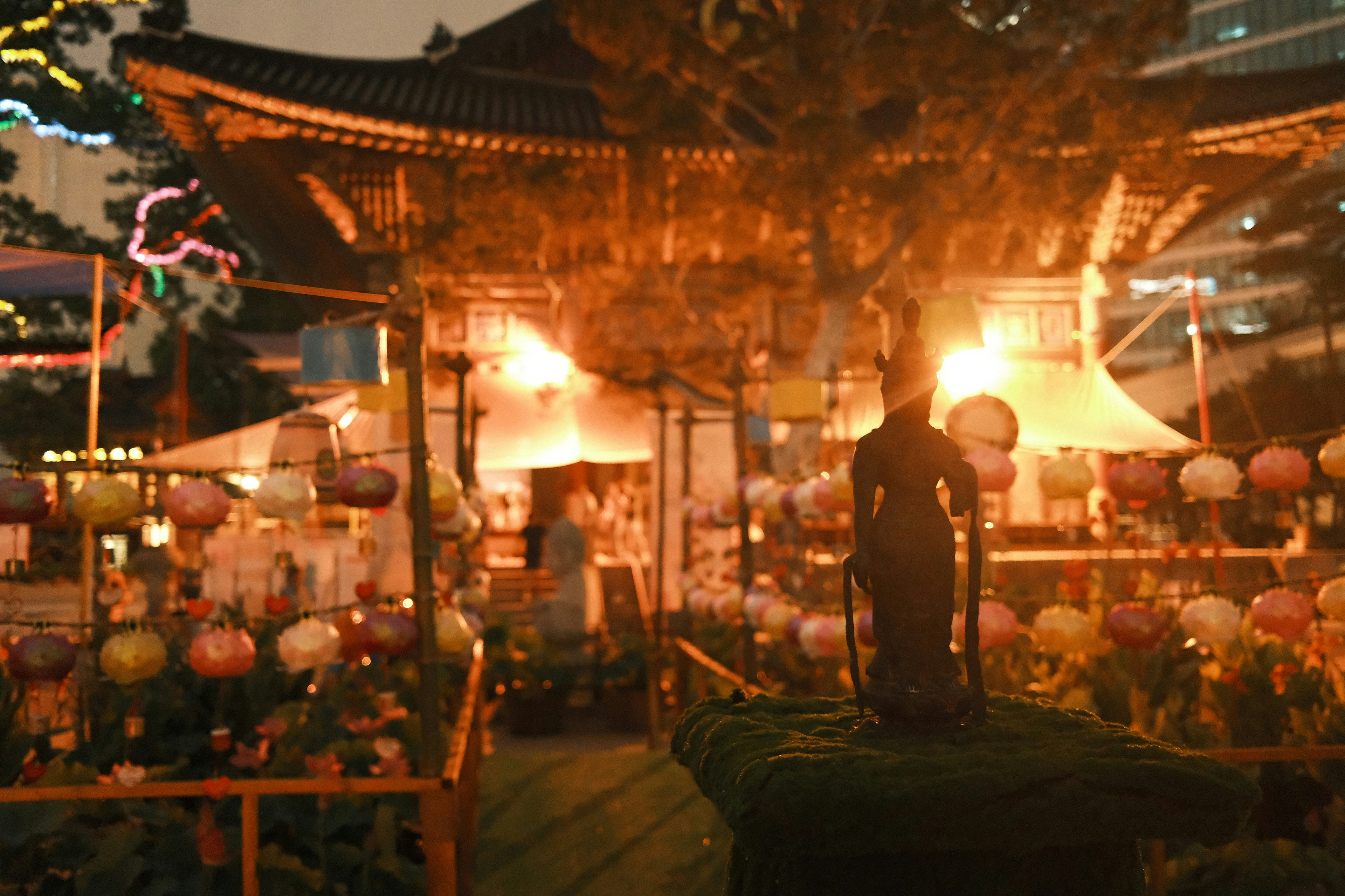 Lantern-lit Shrine at Dusk: A Lone Statue Keeps Vigil over a Festive Night