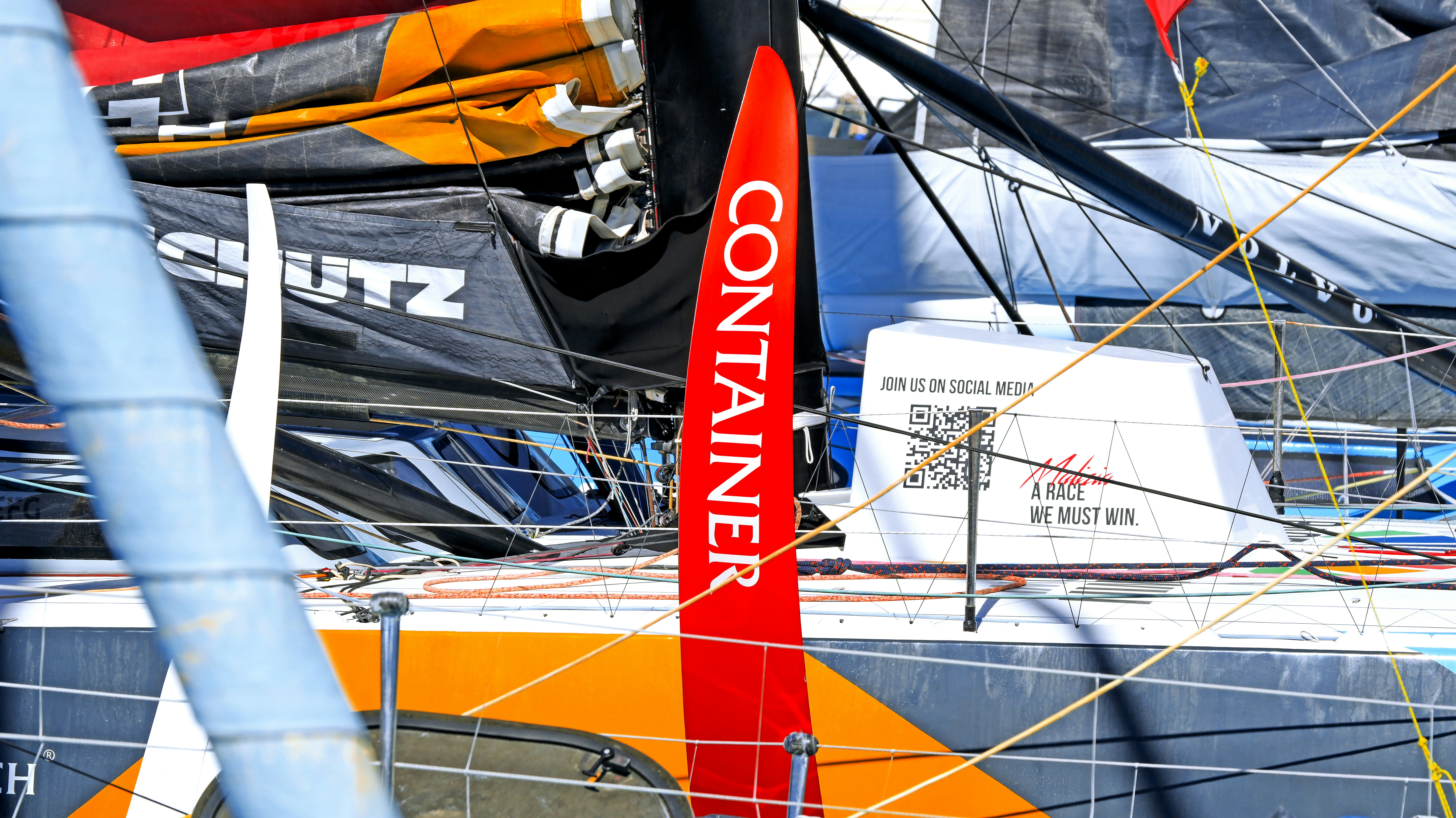 Bright red mast with 'CONTAINER' label rising through a tangle of colorful sails