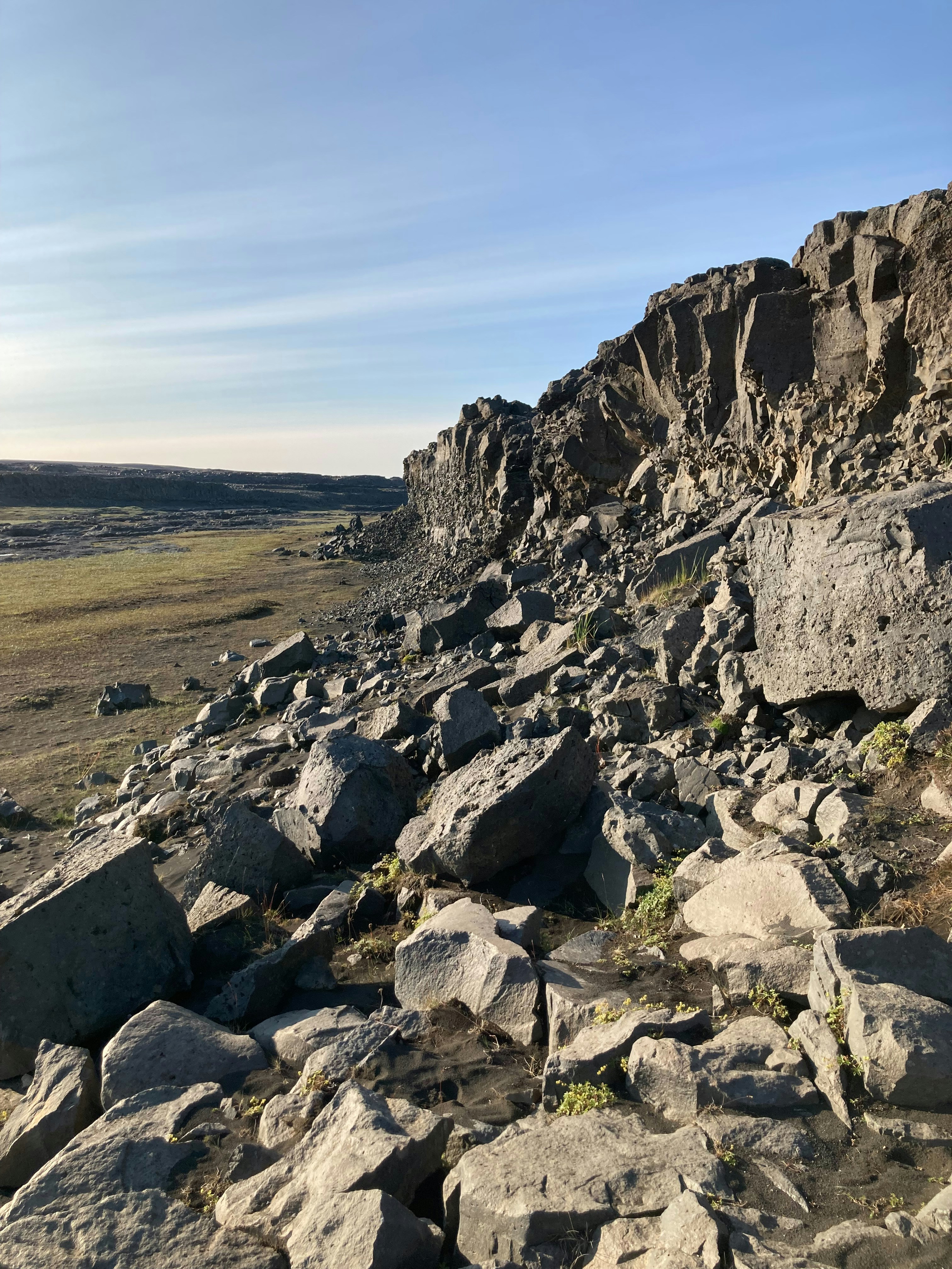 Rugged basalt scree at the edge of a plateau under a clear sky