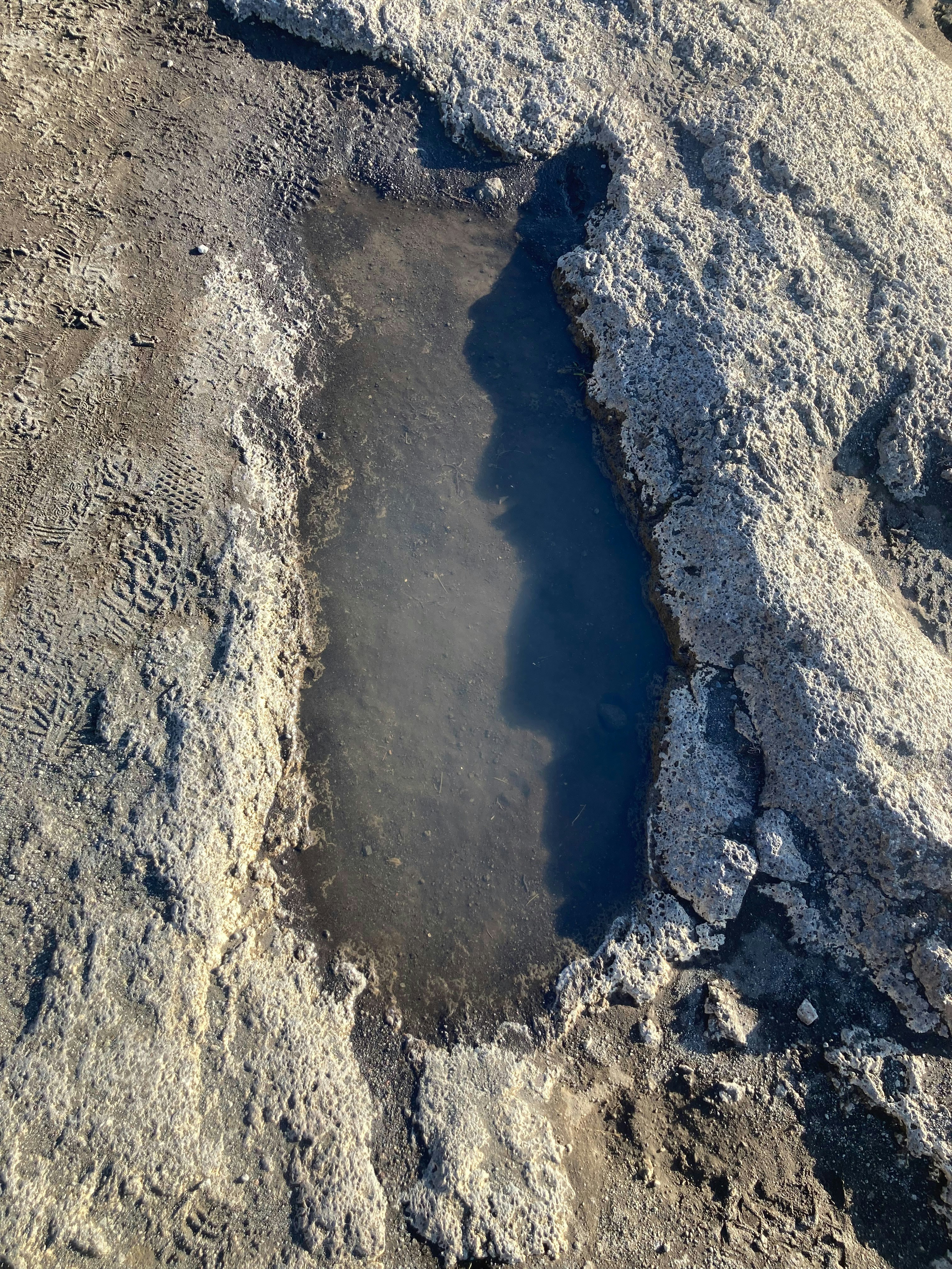 A narrow, glossy water-filled trench carved in sunlit quarry rock