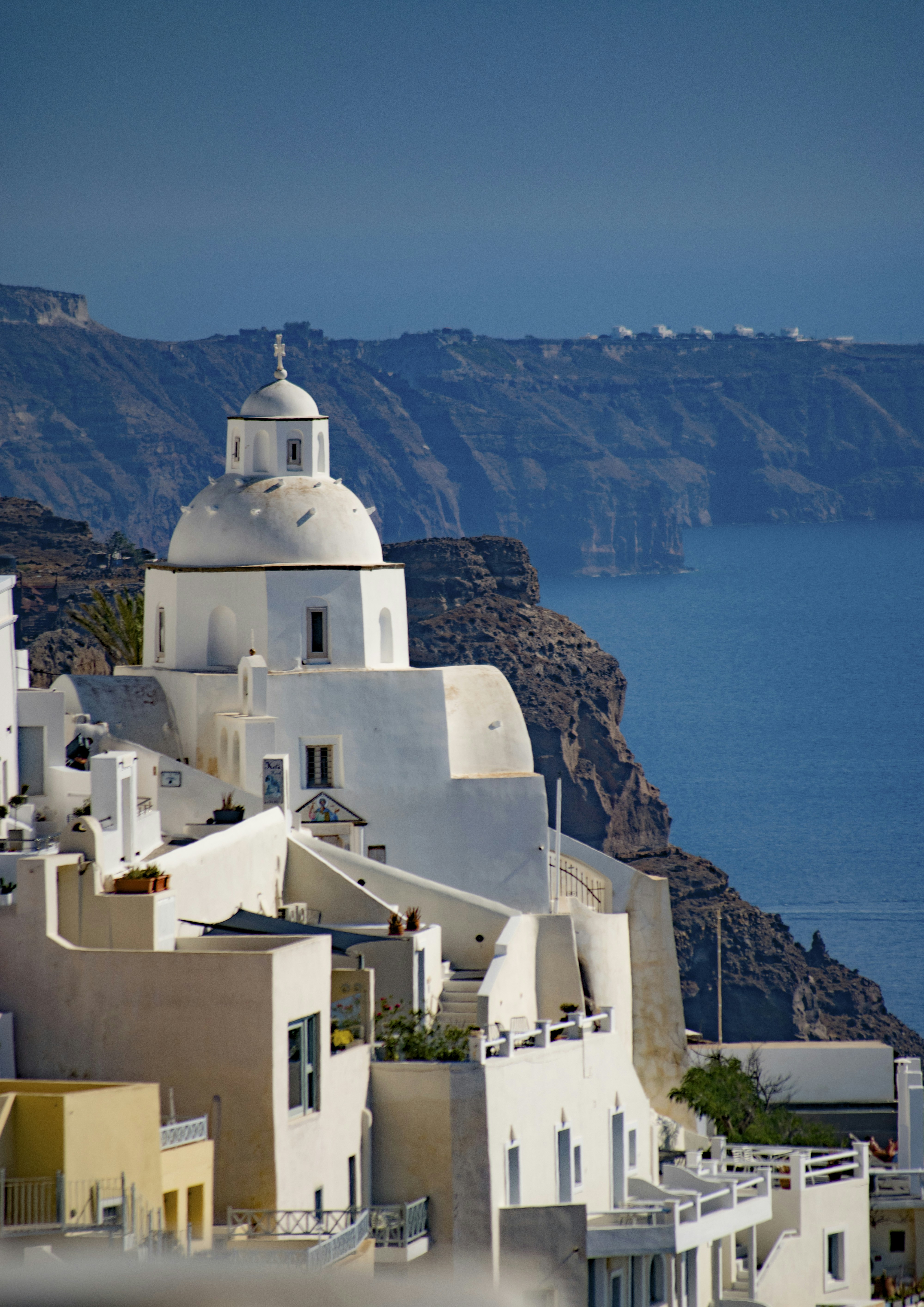 White-domed chapel over a cliffside village in blue Cycladic light