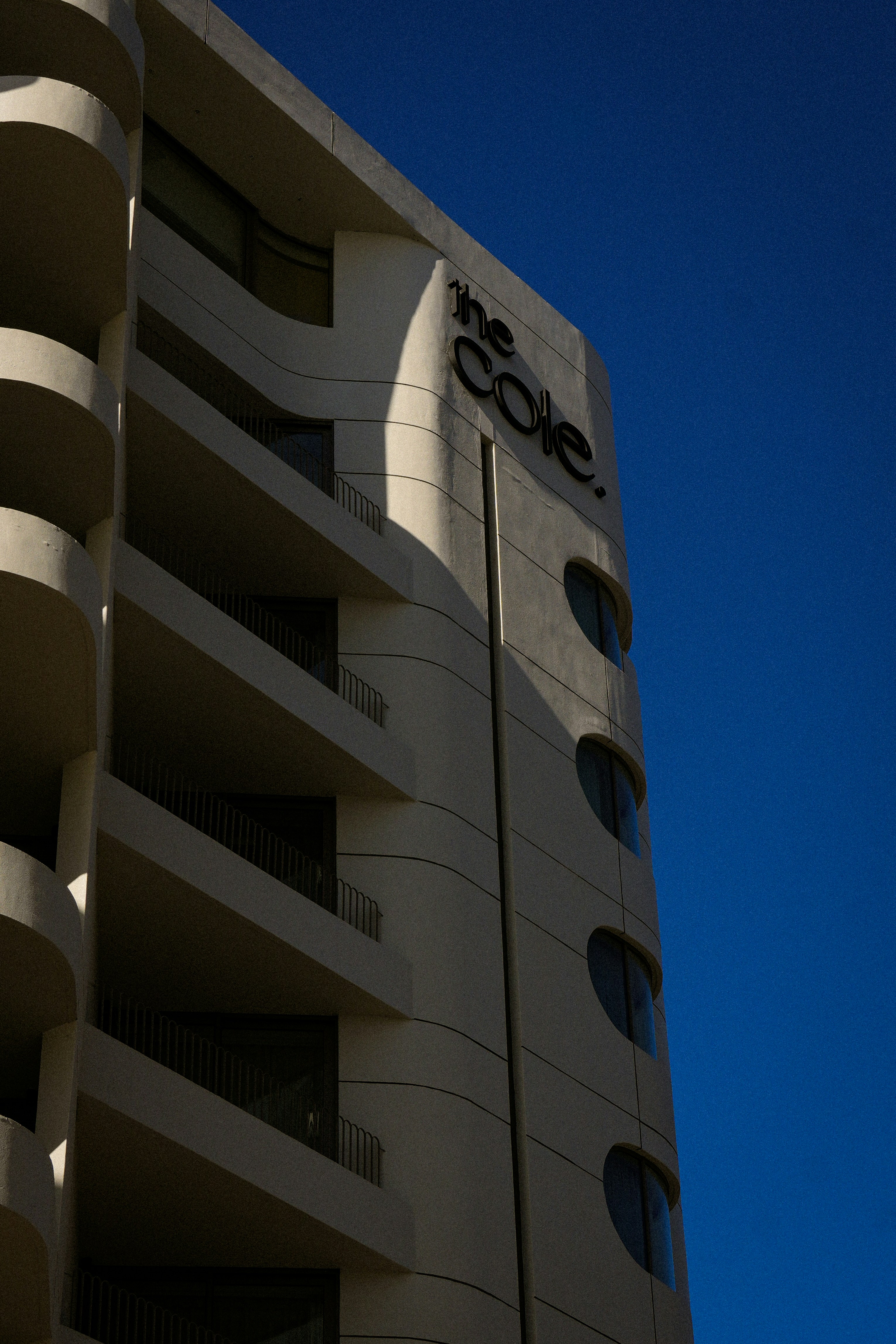 Monolithic Blue: The Curve of The Cole Hotel Against a Vivid Sky