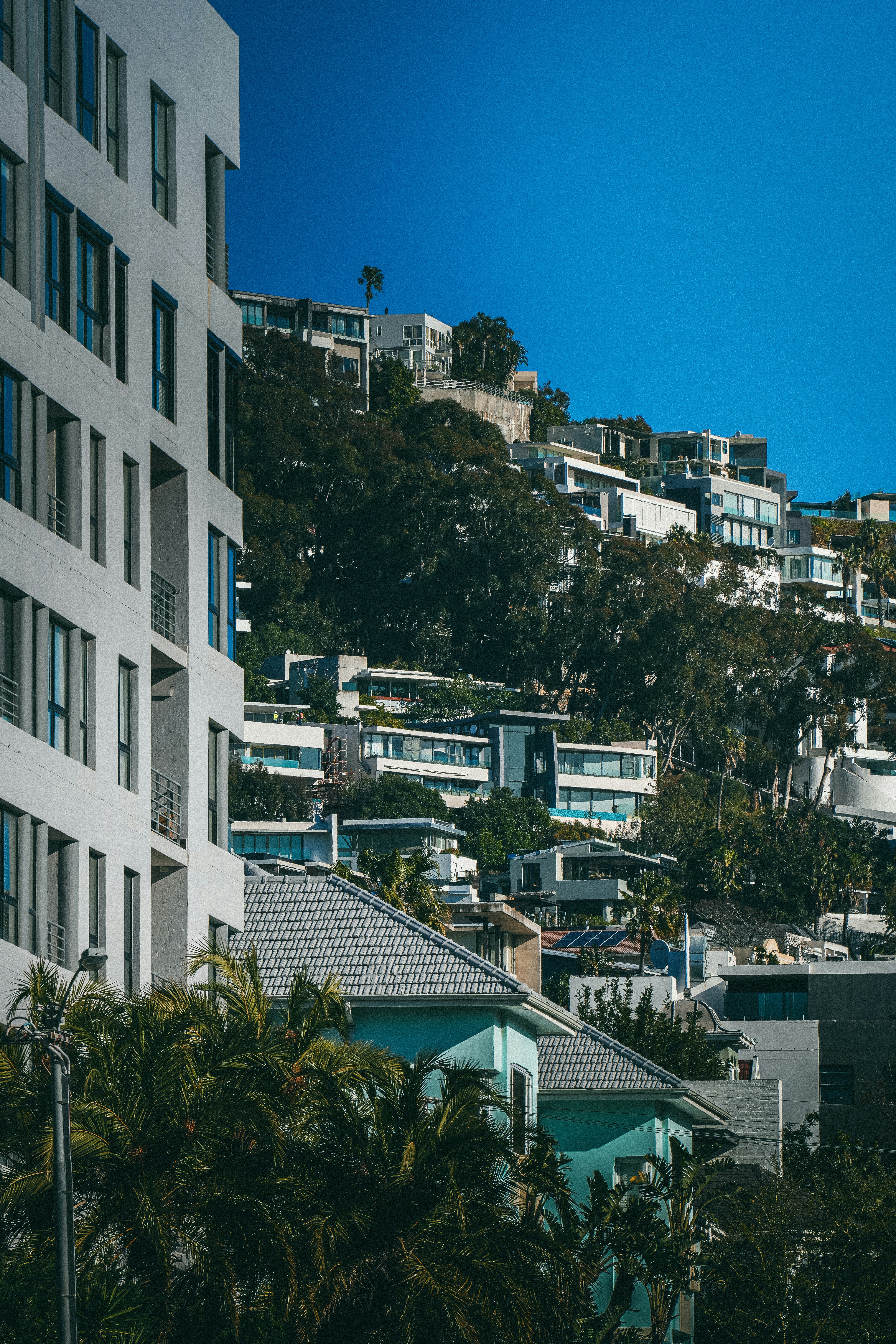Terraced cliffs and modern homes marching up a sunlit hillside
