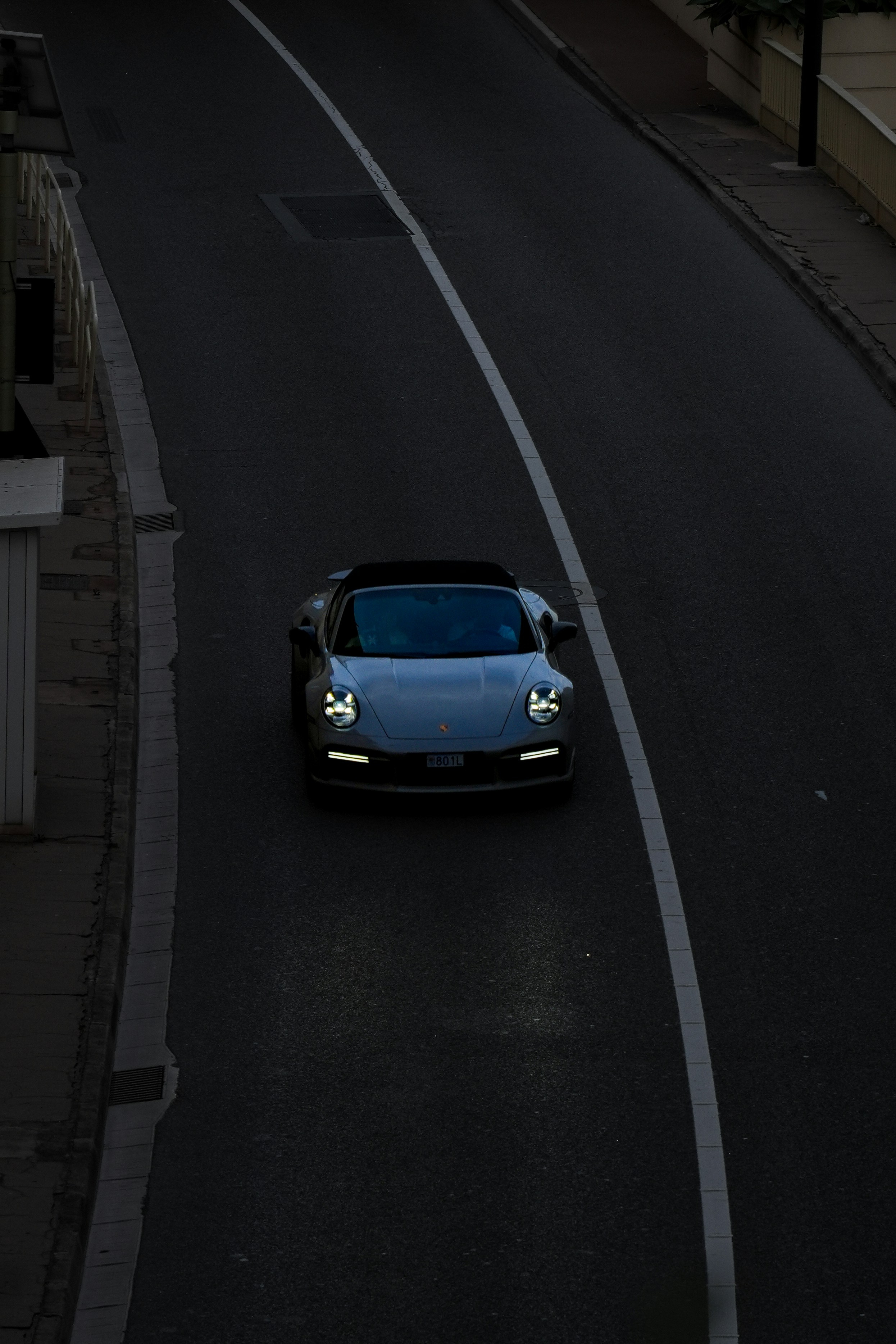 Curved Street Descent: A Porsche under Streetlight Arc