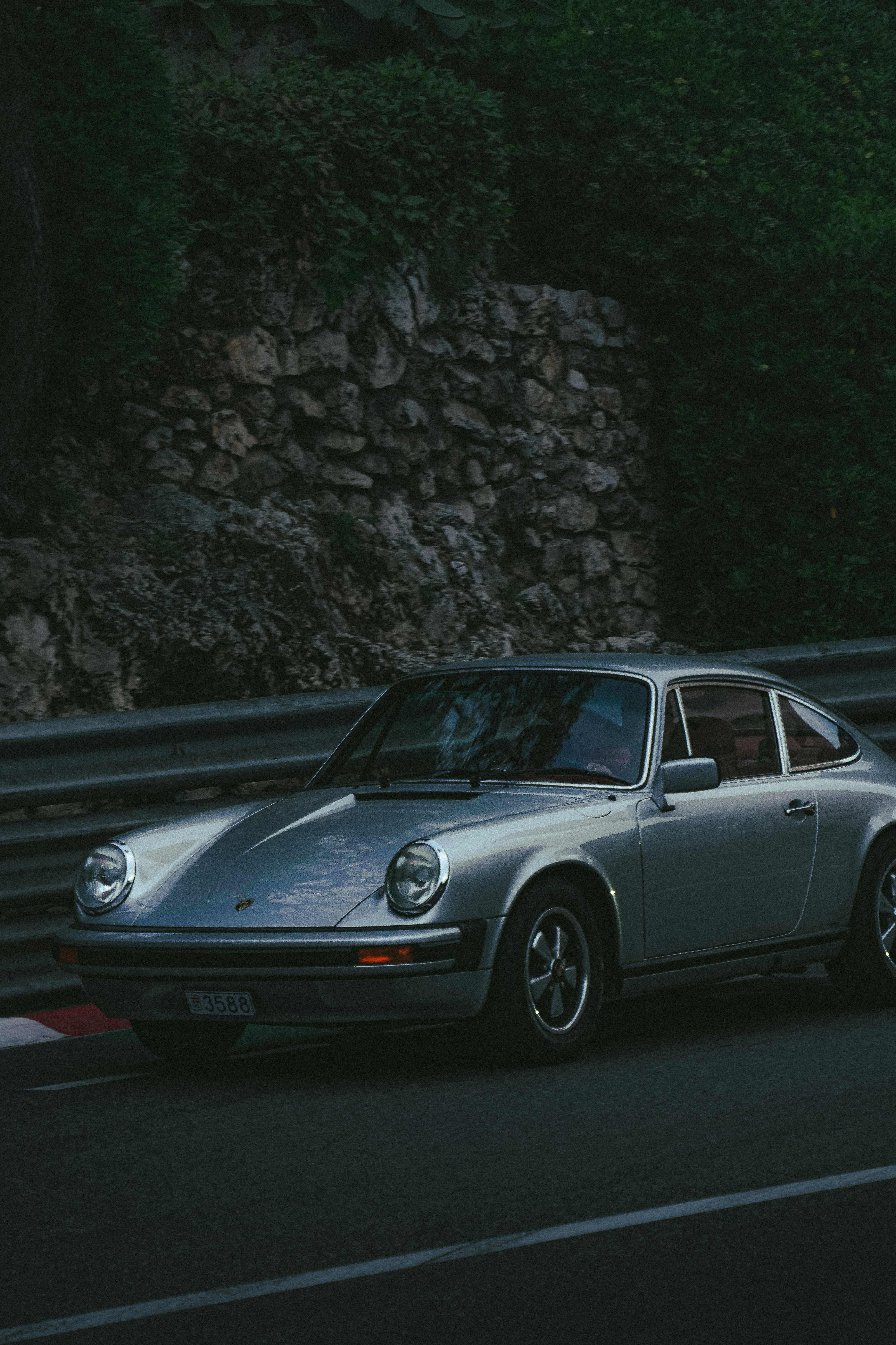 Silver Porsche emerges from the hillside shadows on a winding road