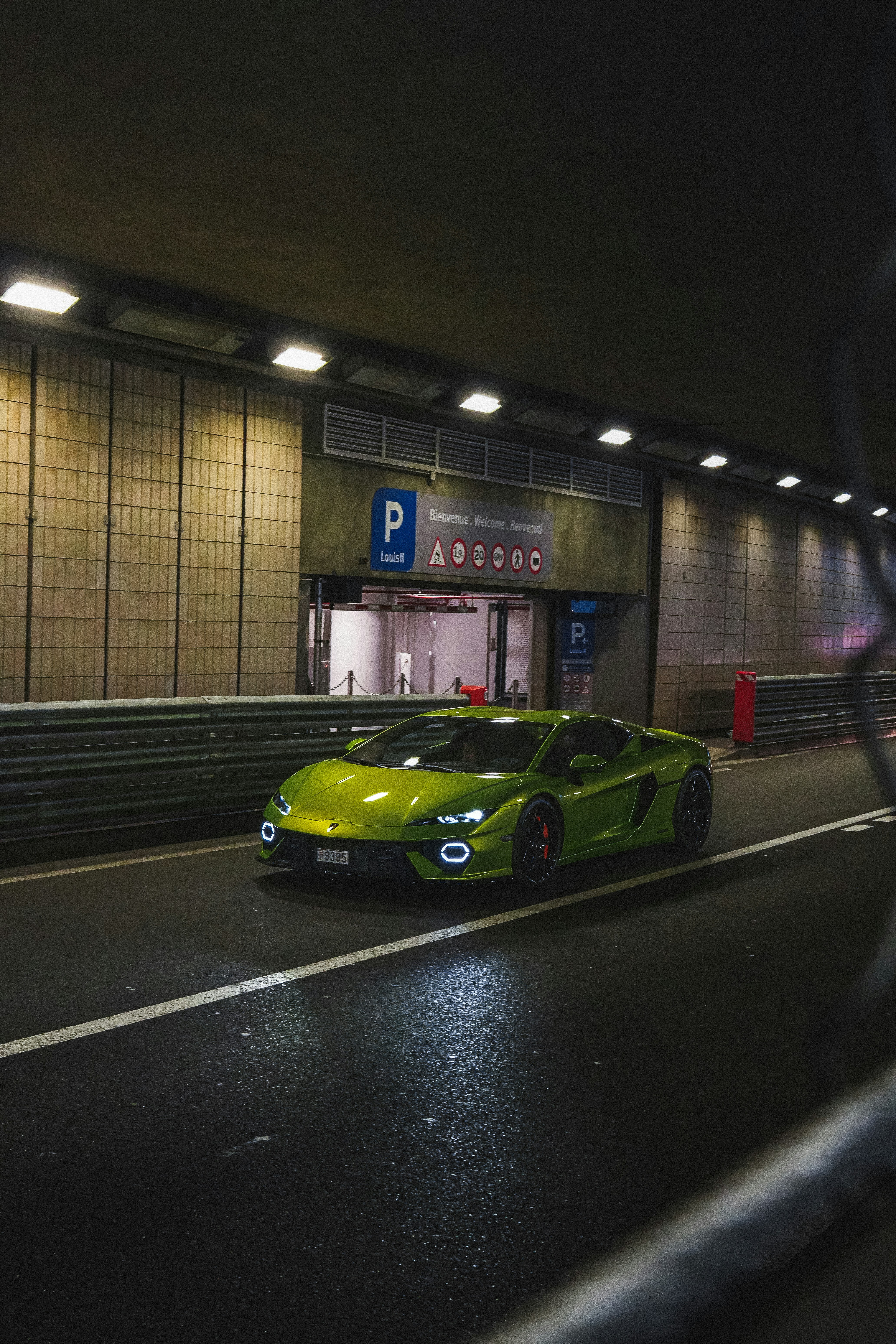 Lime-green supercar exits a tunnel into neon evening rain