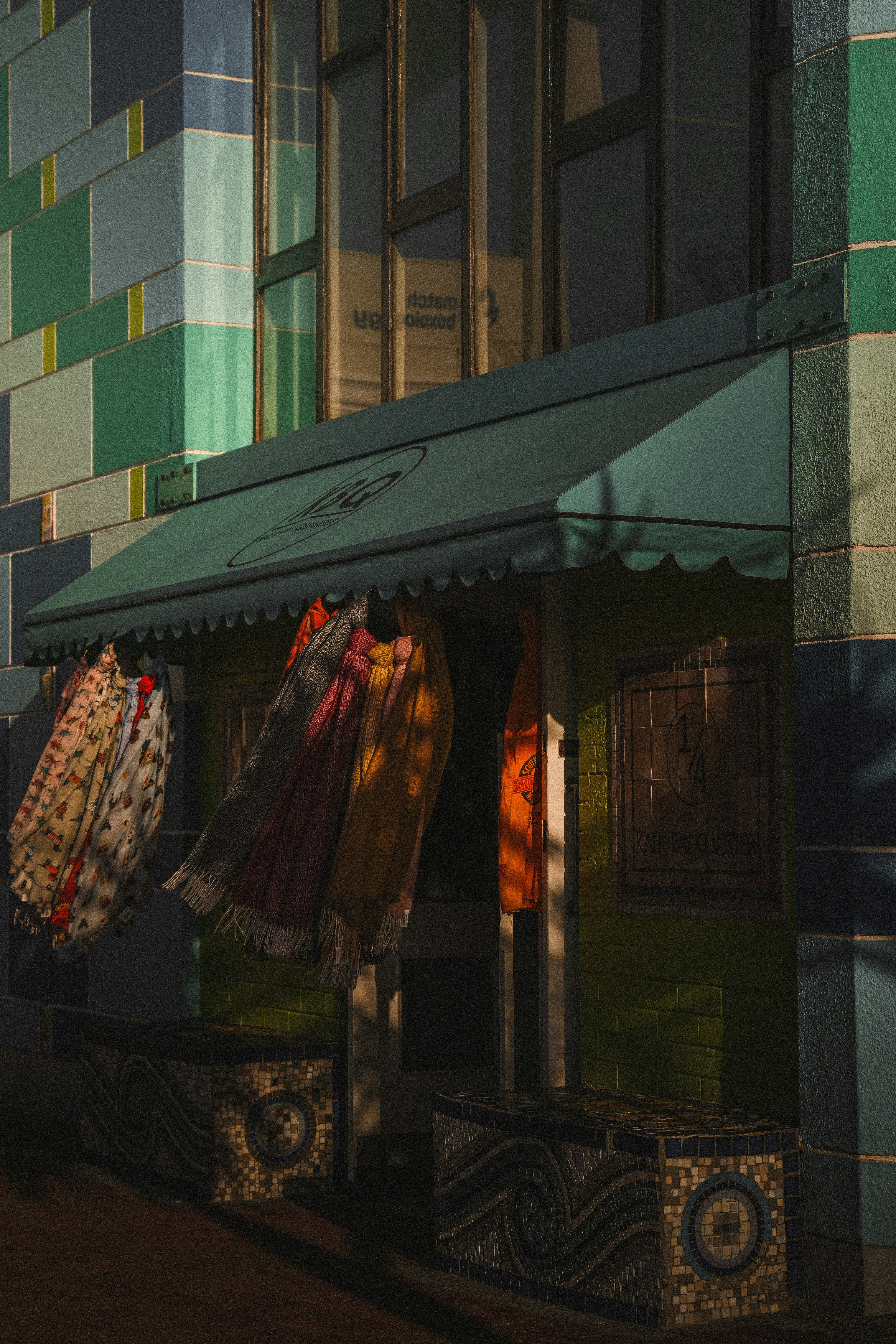 Shaded storefront: scarves under a teal awning