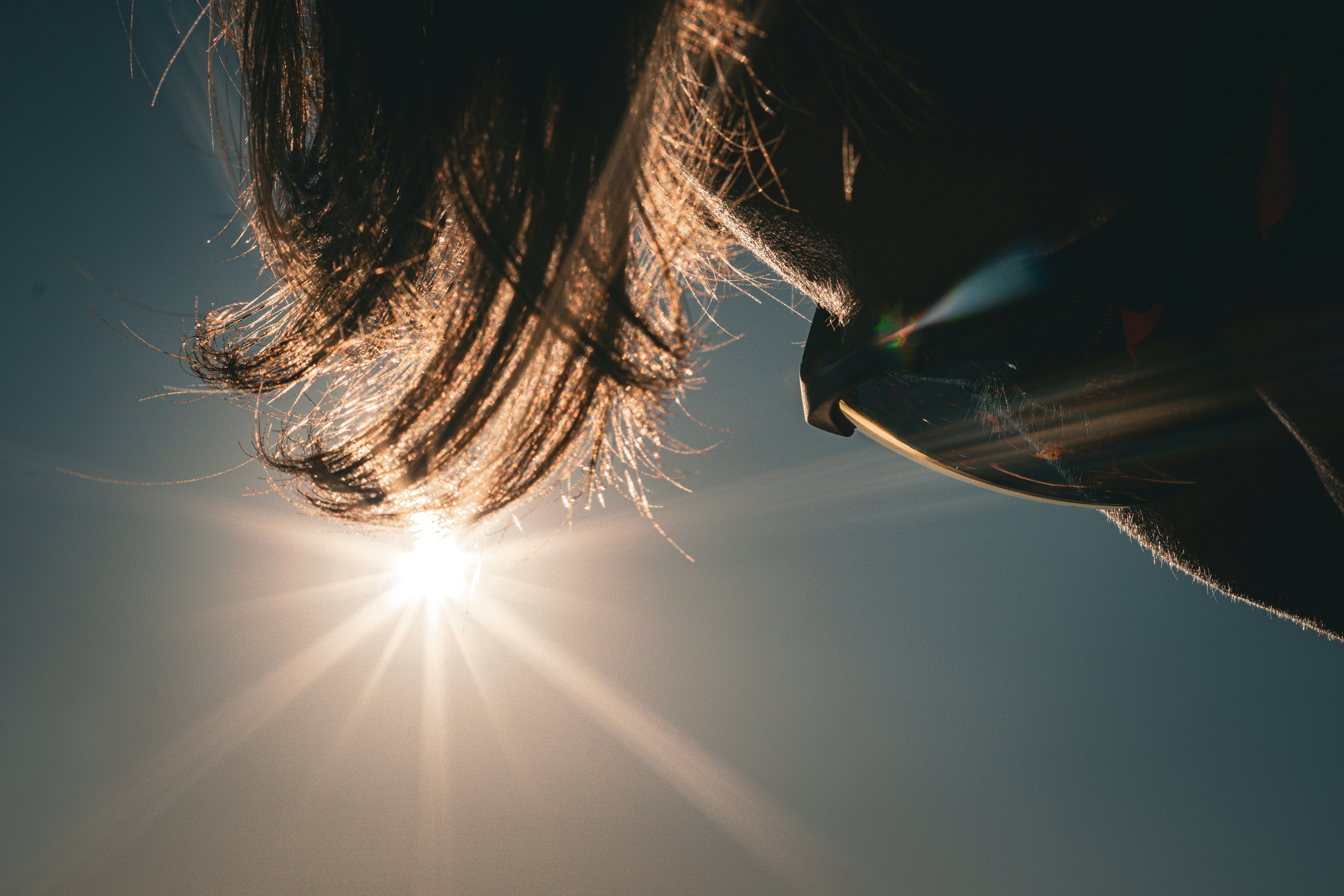 Sunlit fringe: a profile of light and hair against the flare