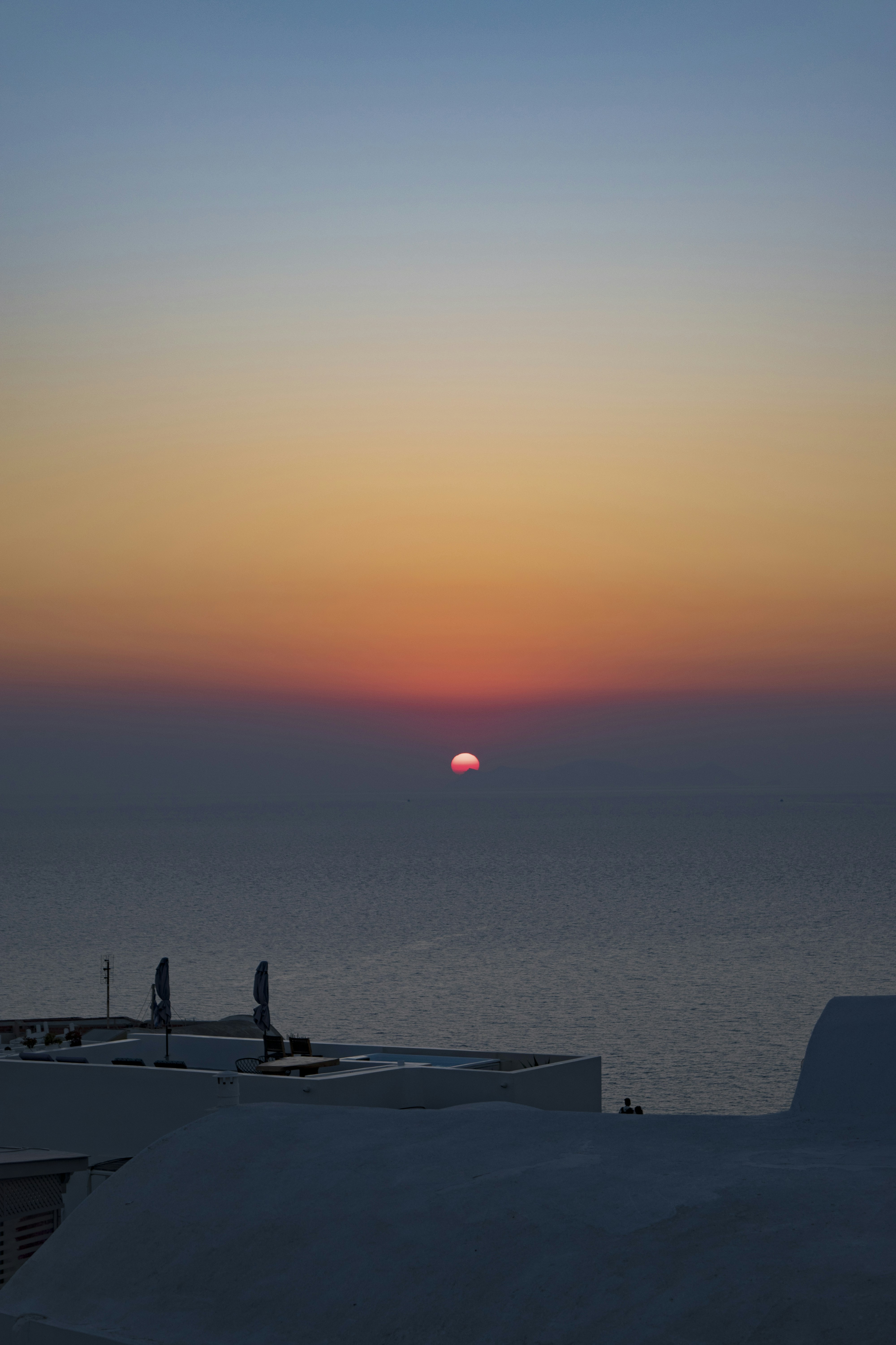 Red Sun at the Horizon over Quiet Sea with White Architecture Foreground