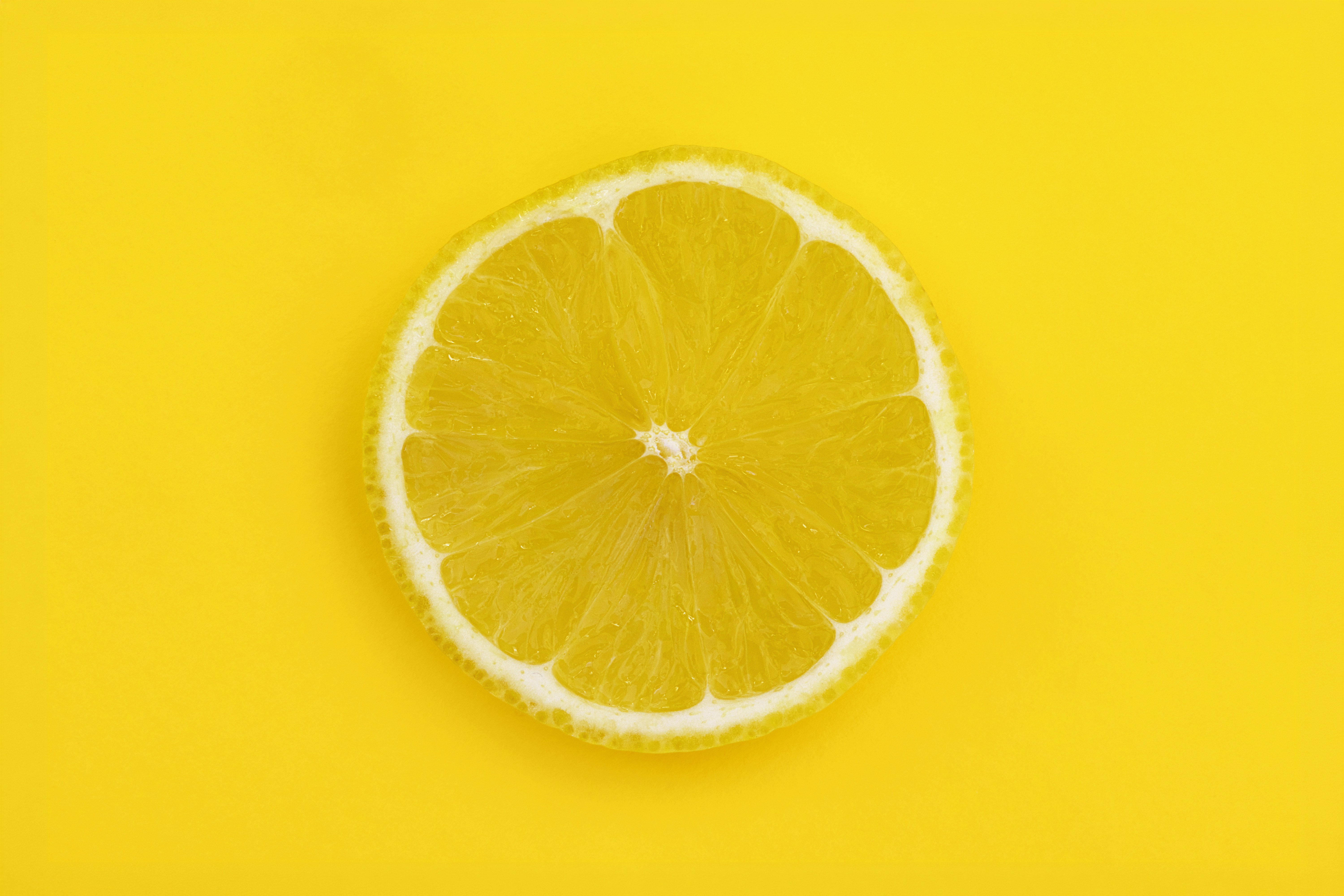 Sunny Citrus Reveal: A Floating Lemon Slice Against a Bright Yellow Backdrop