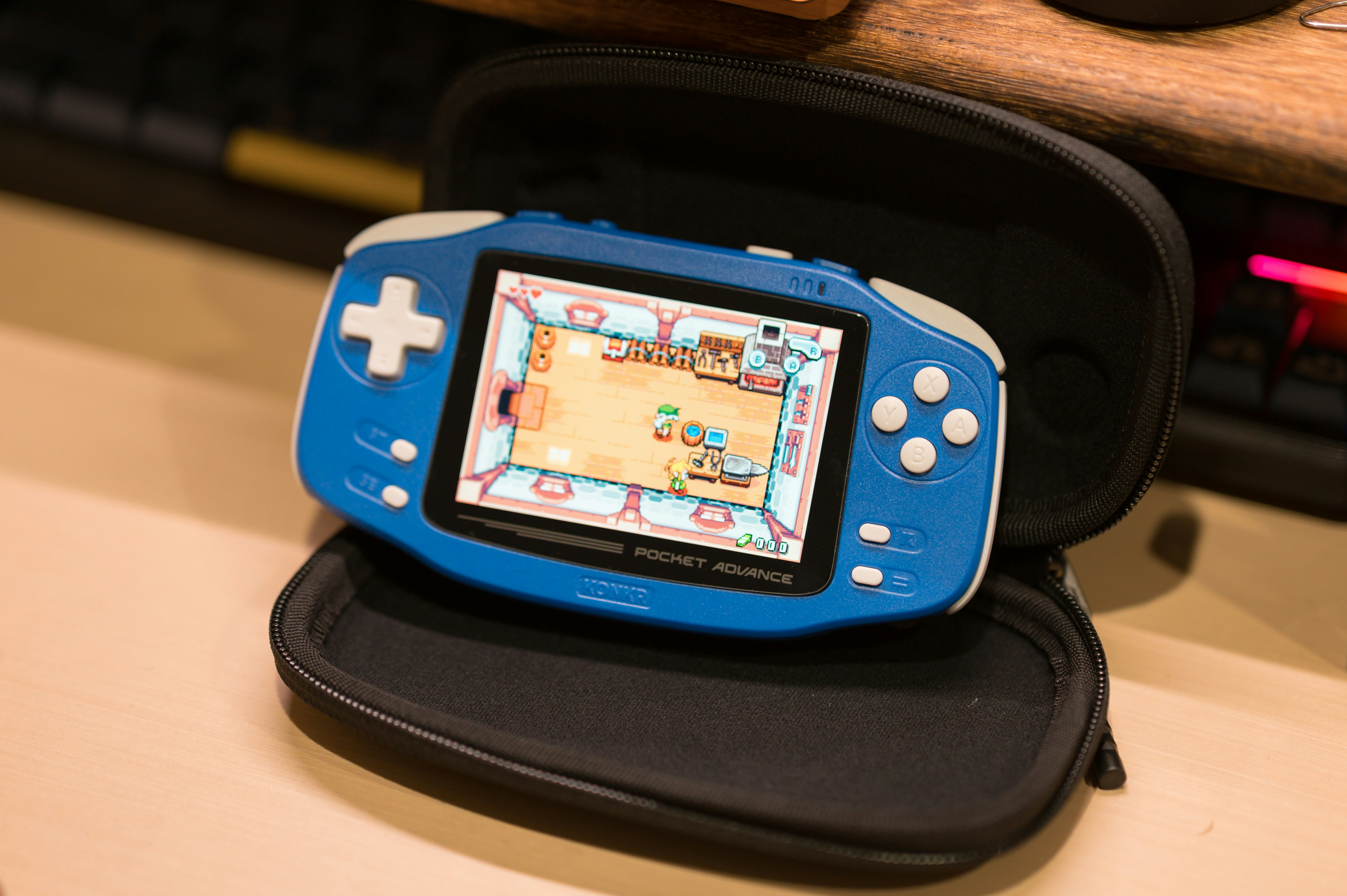 Pocket Arcade: A Blue handheld rests in a soft zip case on a wooden desk