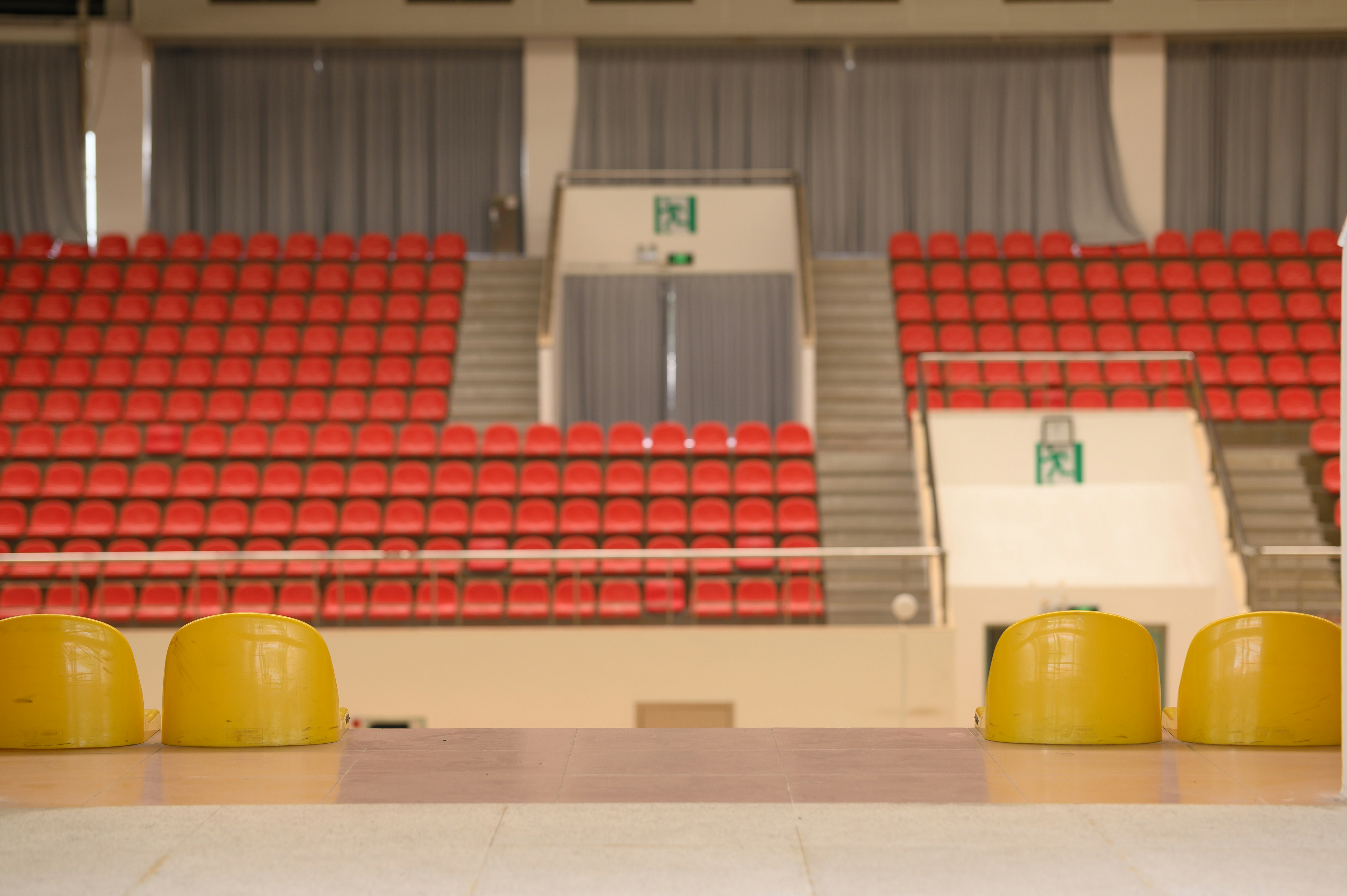 Empty arena: red seats and yellow barriers framing a silent threshold
