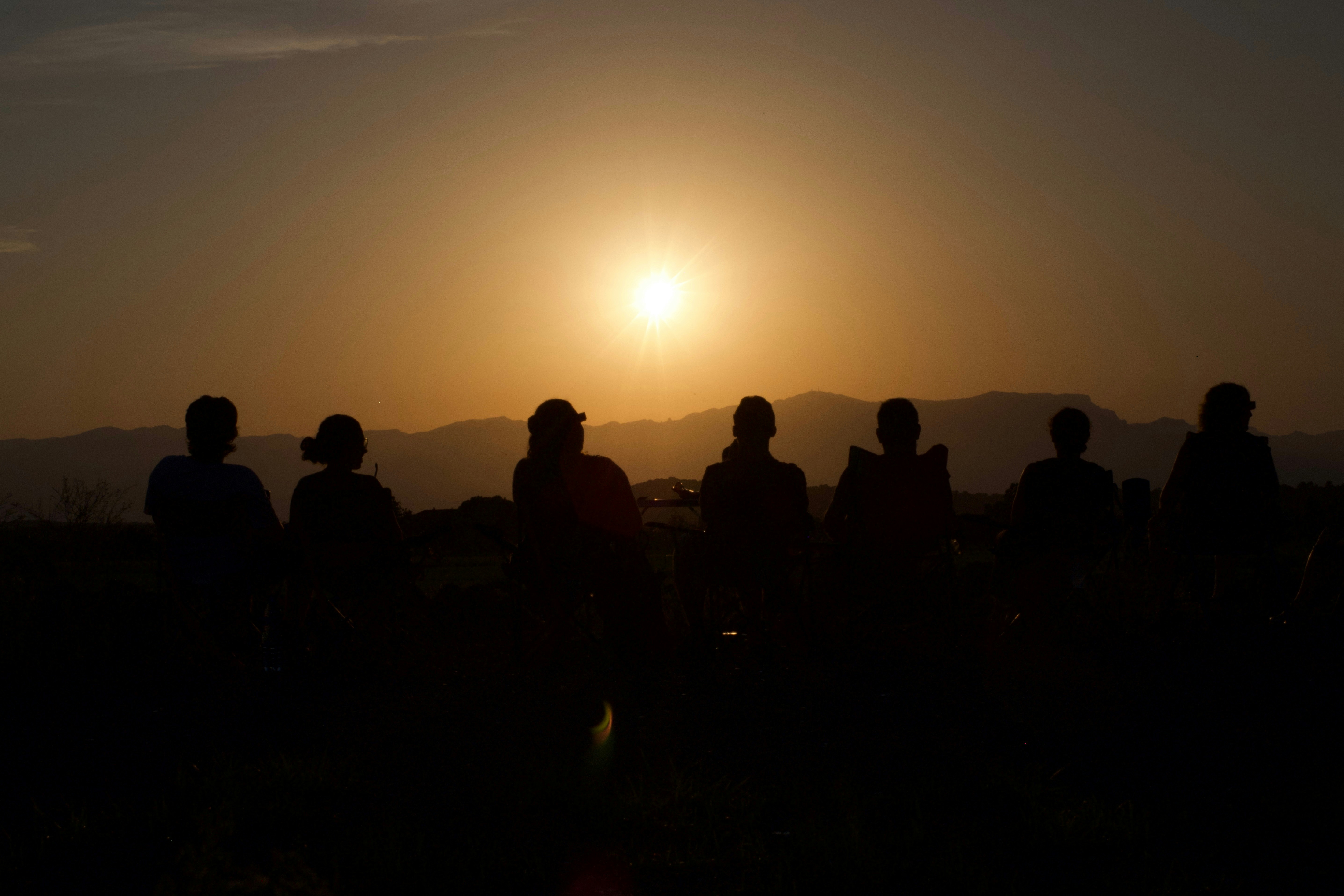 Sunset Silhouette: A Circle of Voices Against the Distant Hills