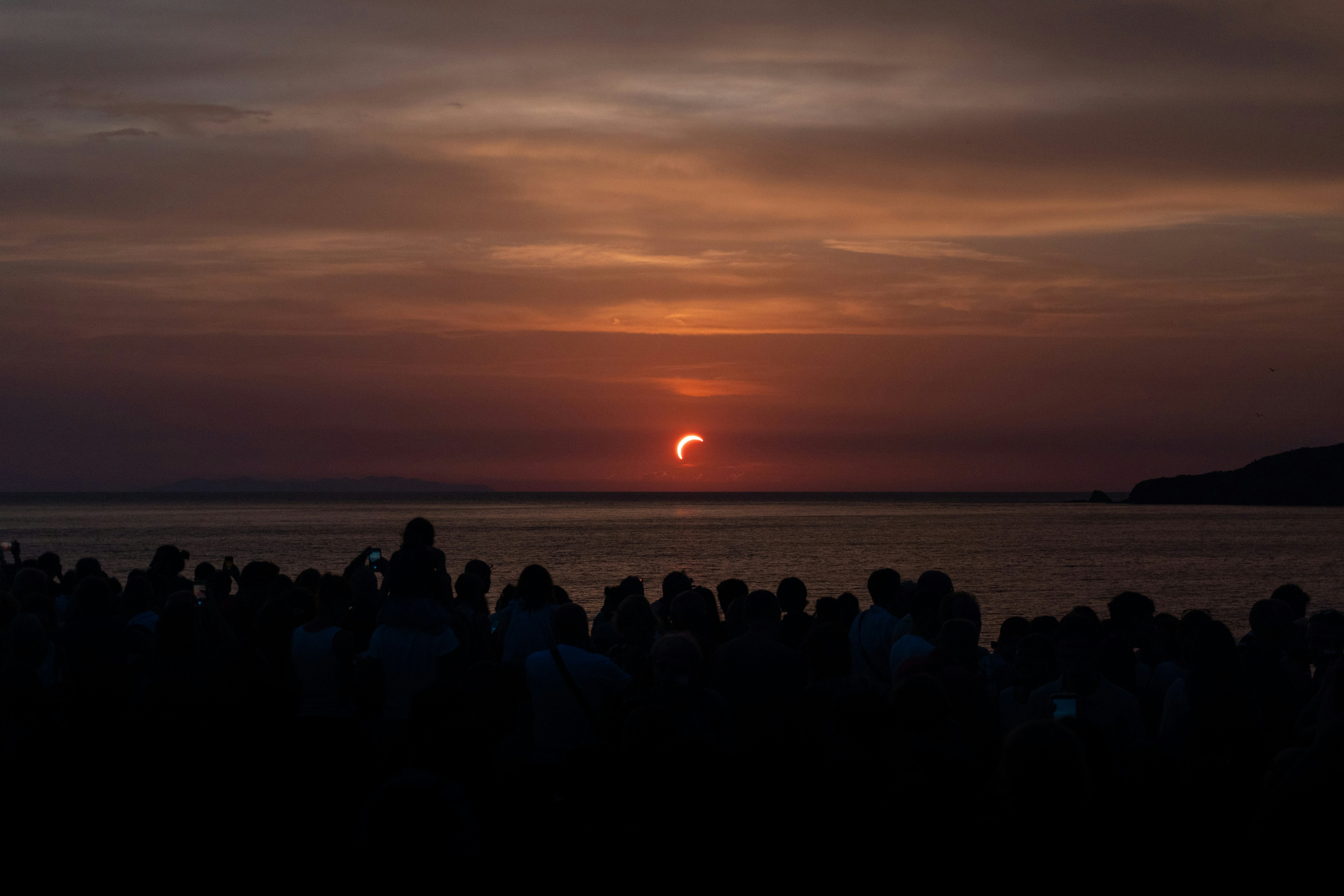 Silhouette Chorus at Sunset: A Crescent Moon over the Crowd