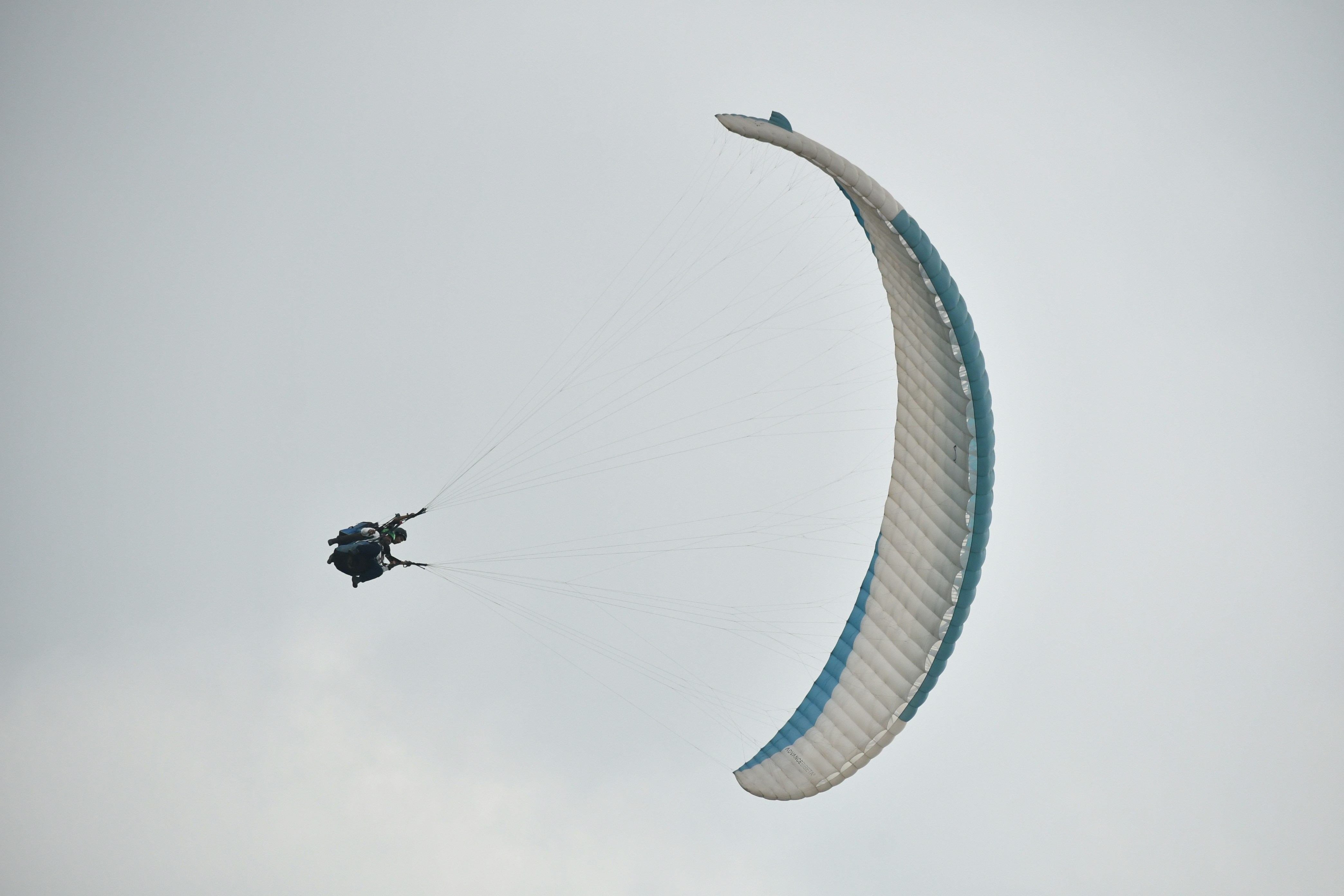 Graceful Glide: A lone paraglider cuts through a pale sky
