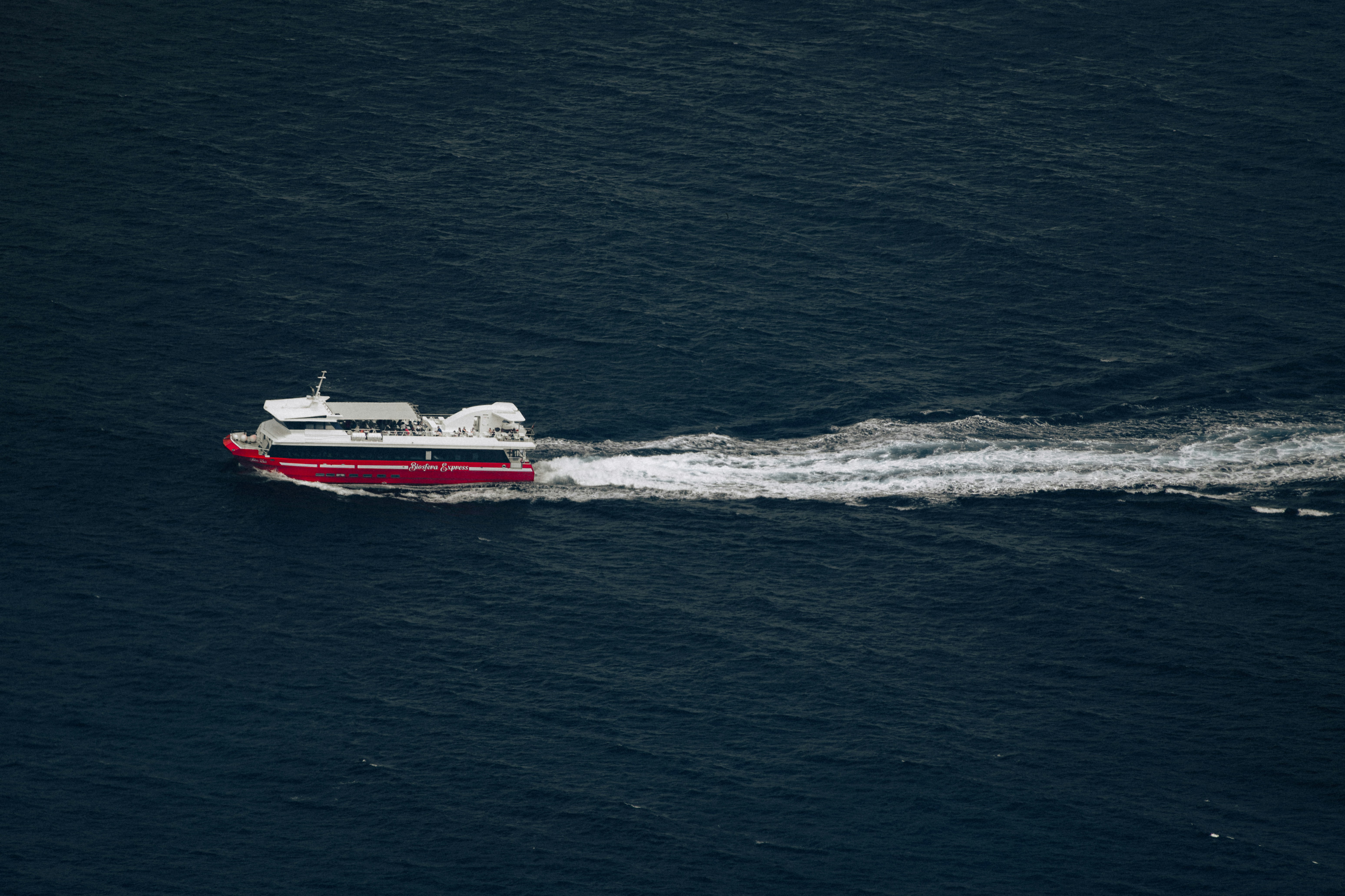 Red and White Vessel Cutting Through Open Sea