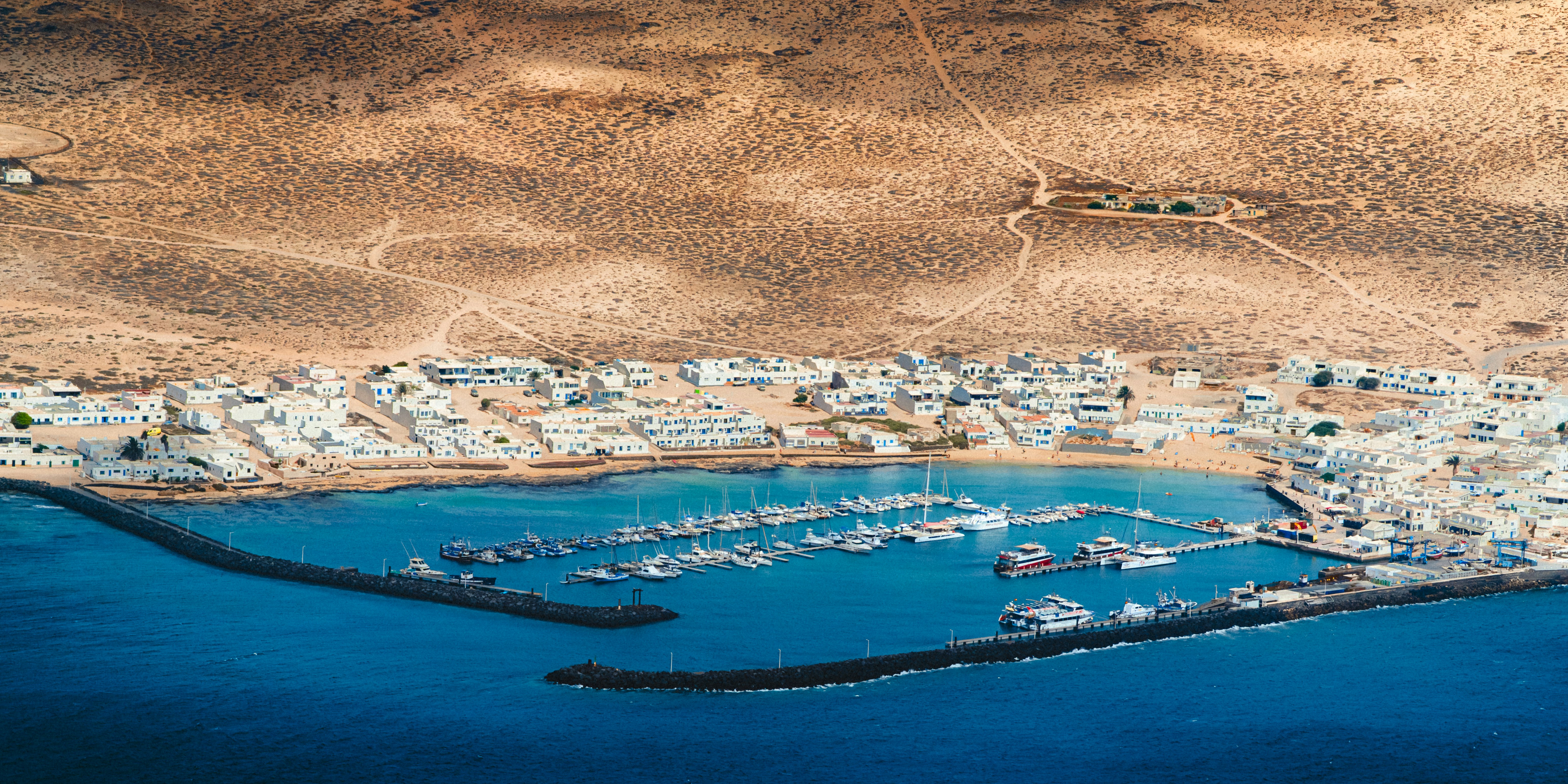 Harbor Arc: Boats, Breakwater, and a Sunlit Village
