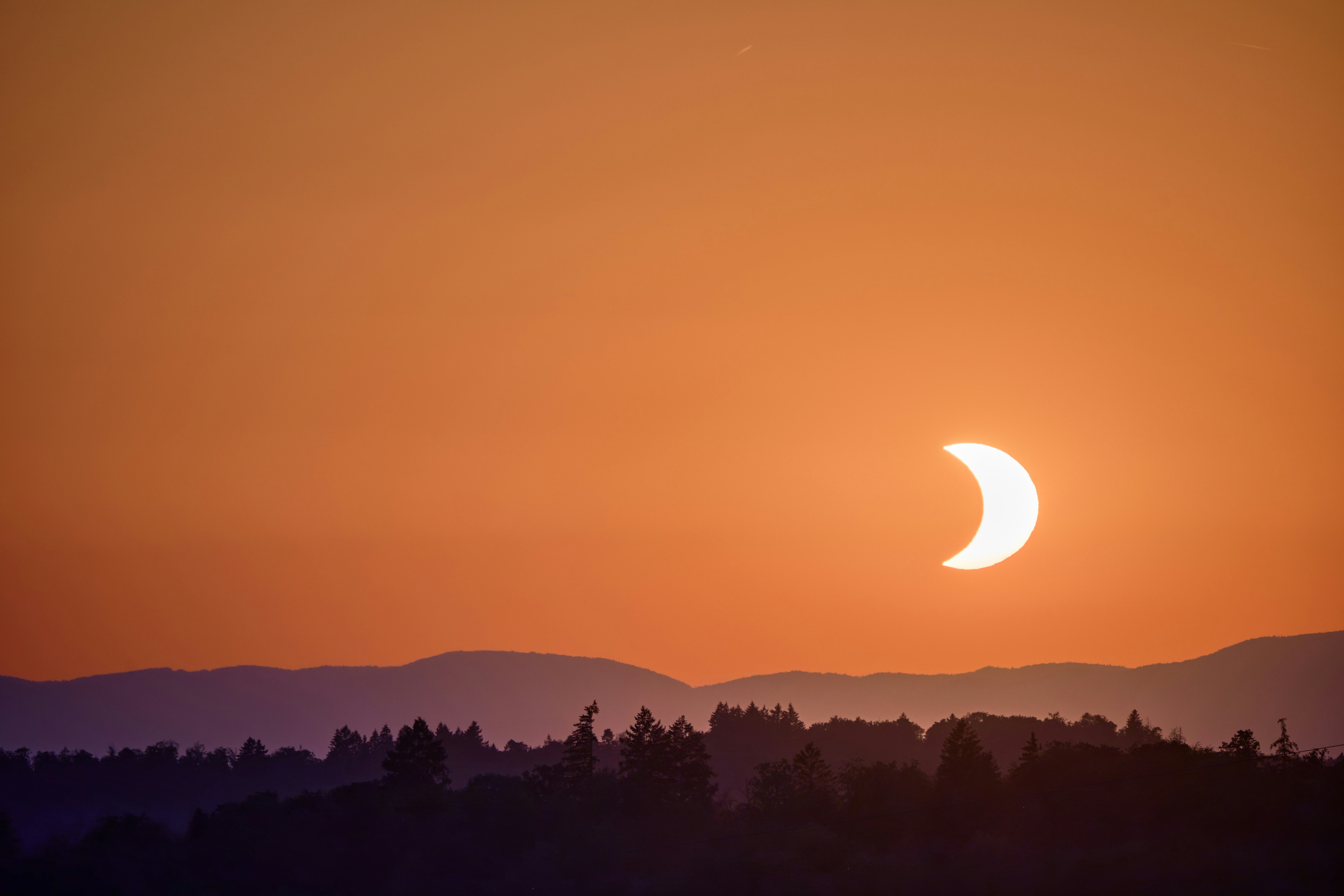 Crescent in the Ember Sky Over Silhouetted Hills
